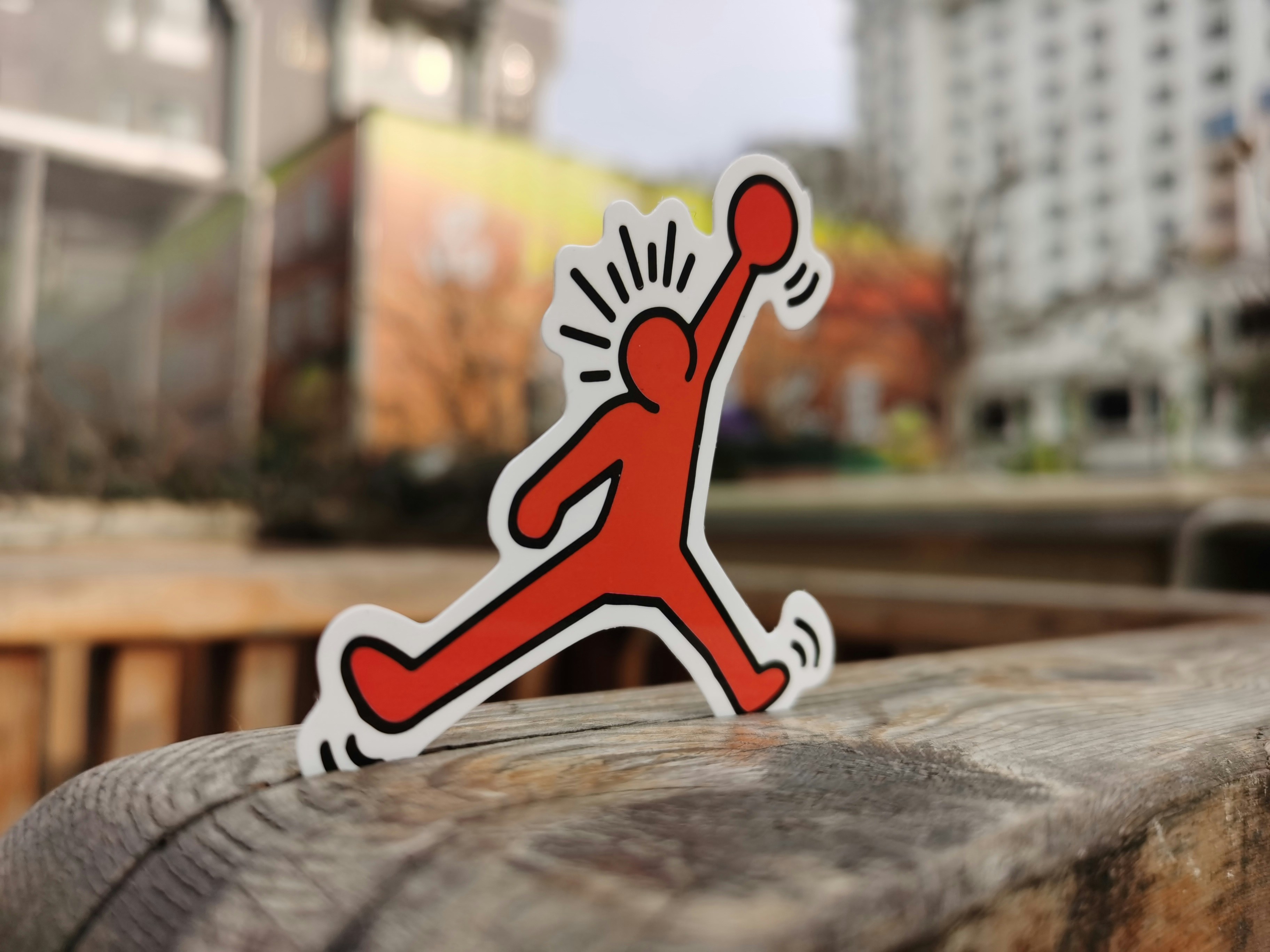 Red Jumping Figure on Weathered Wood: Mini Sticker in Urban Plaza