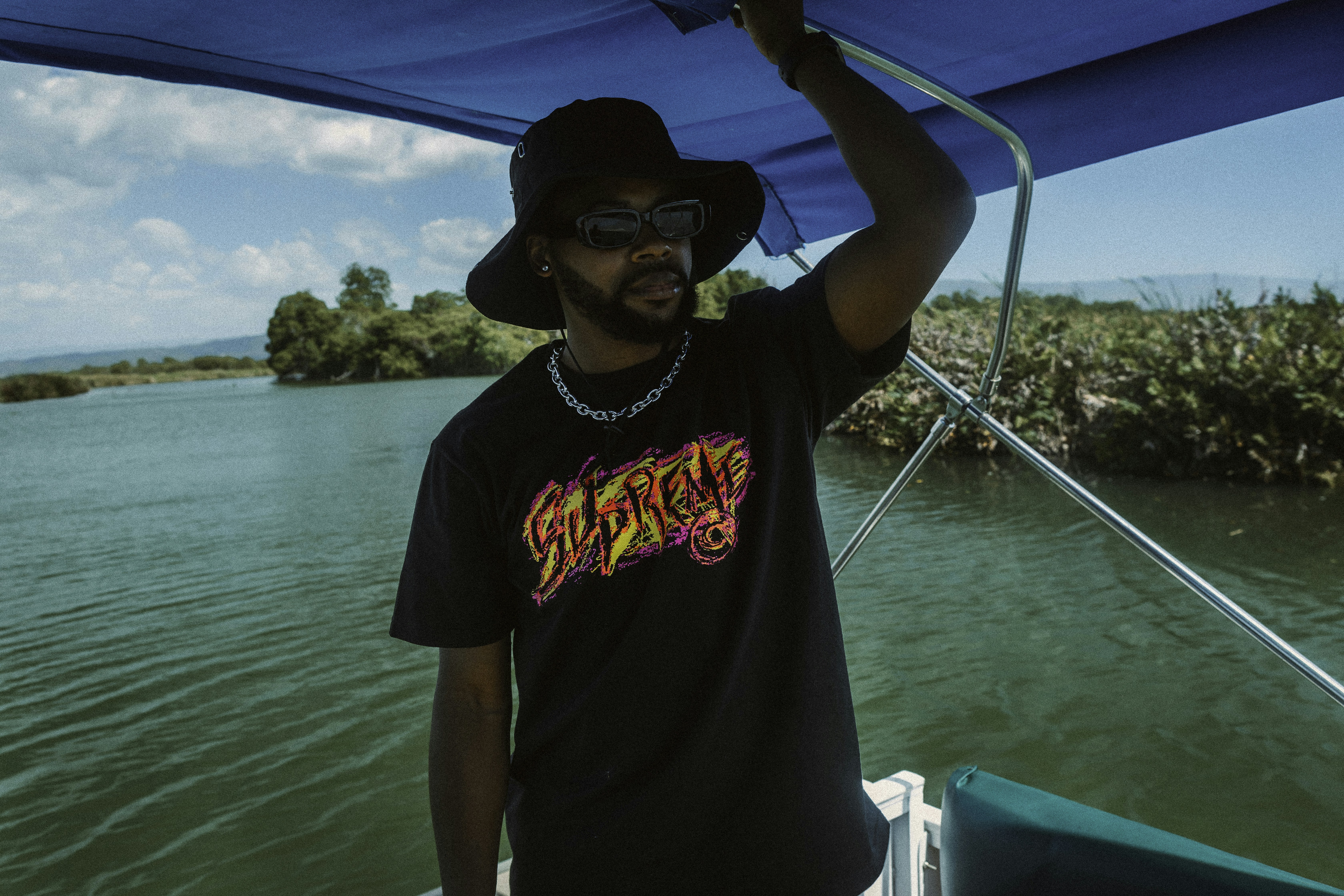 man in black crew neck t-shirt wearing black hat standing on boat during daytime