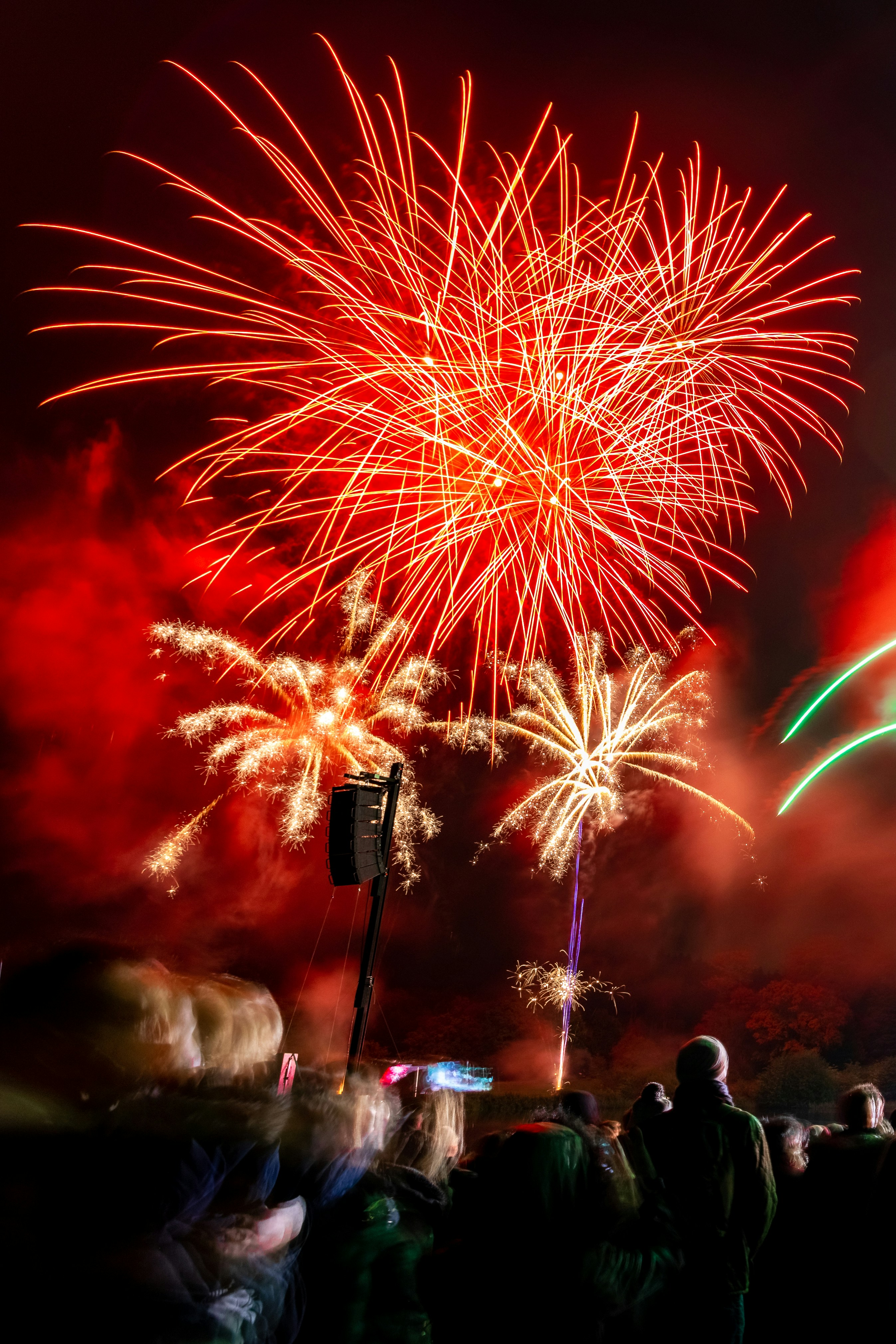 Vibrant red fireworks burst in the night sky above a crowd at Leeds Castle.