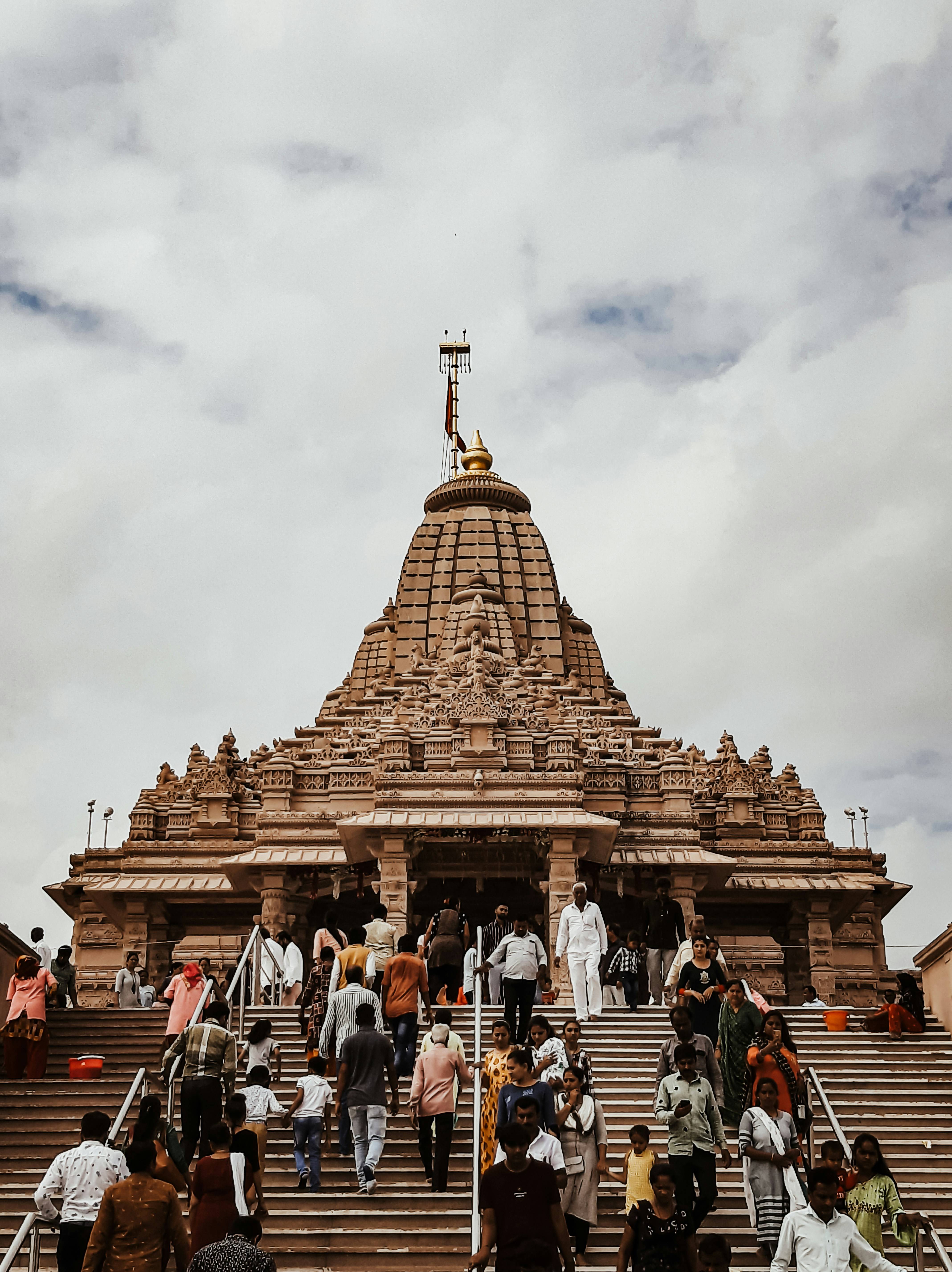 people walking on street near brown concrete building under white clouds during daytime