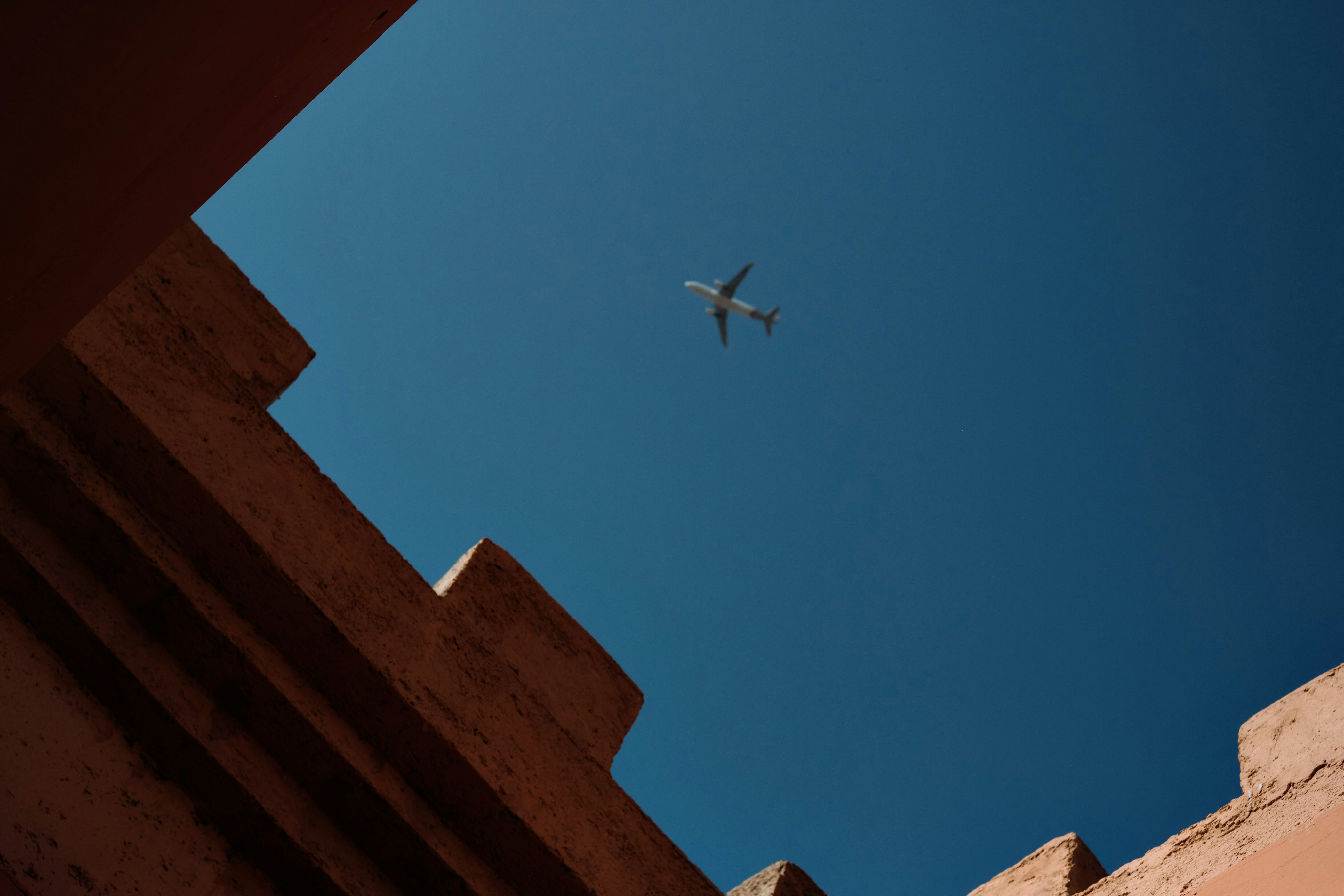 Skyward Crossing: A Plane Above Terracotta Geometry