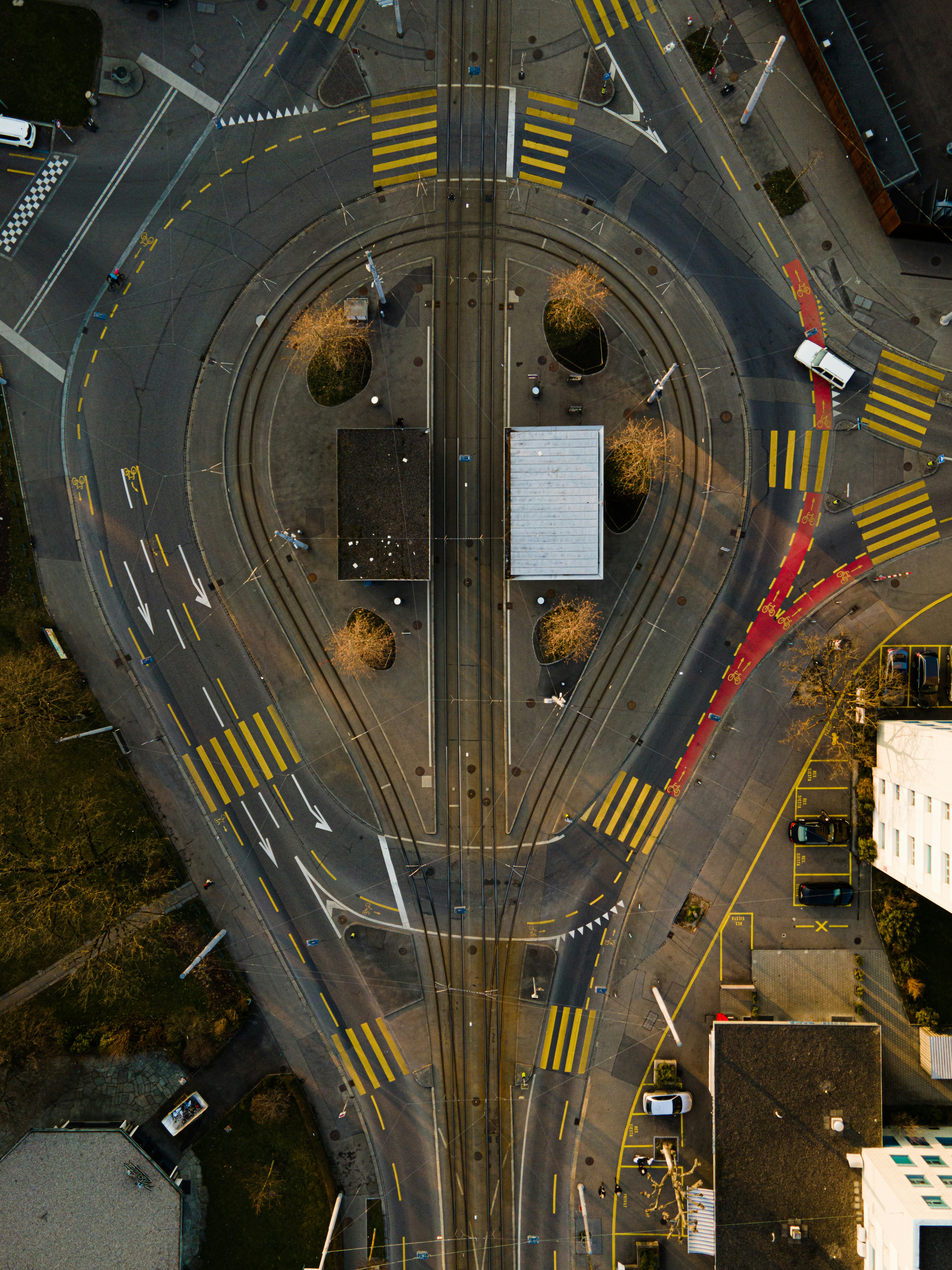 Aerial view of a circular intersection showcasing intricate road patterns and pedestrian zones, with trees and a central structure enhancing the urban landscape.