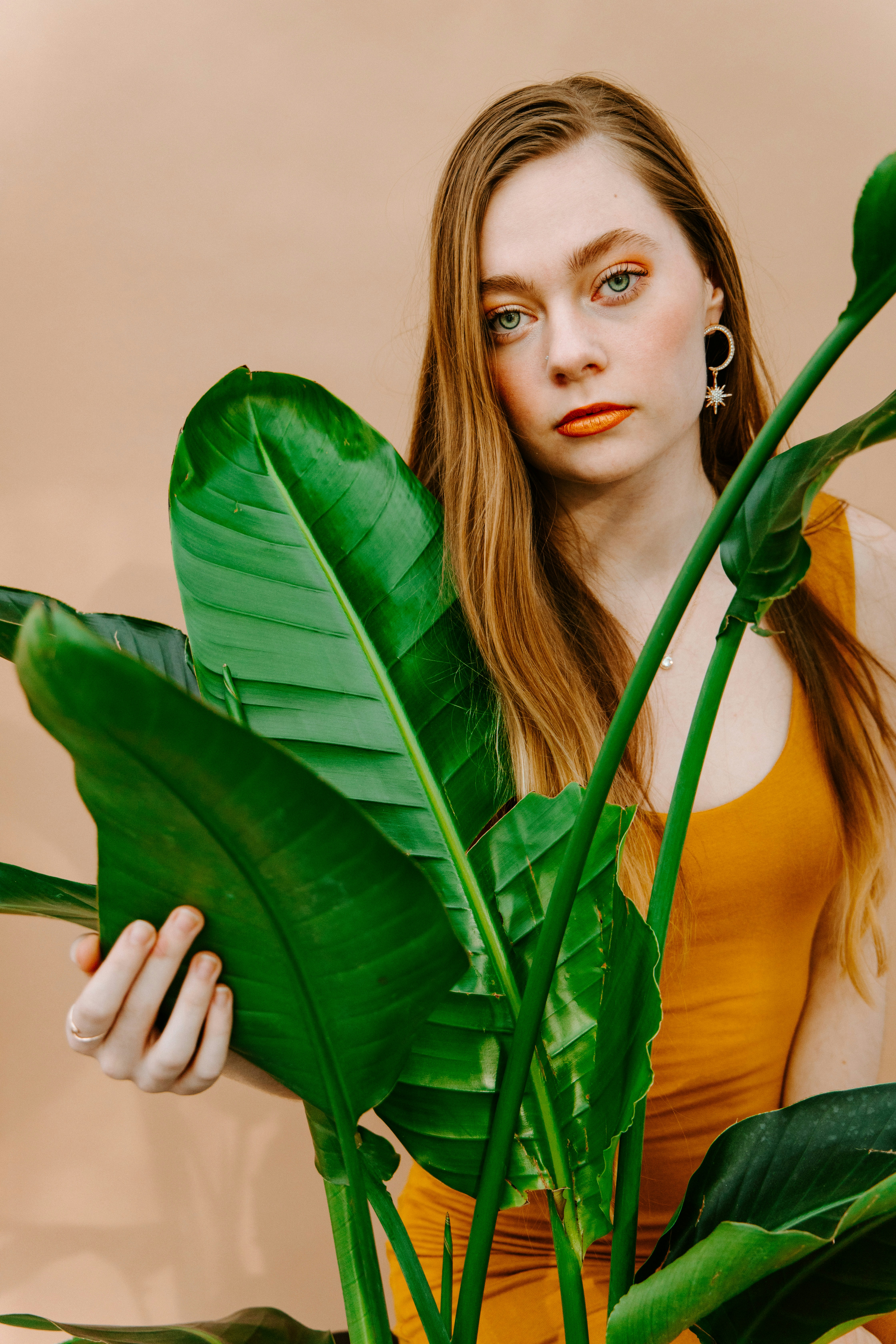 Amber Portrait Behind Tropical Foliage: A Quiet Gaze Through Giant Leaves