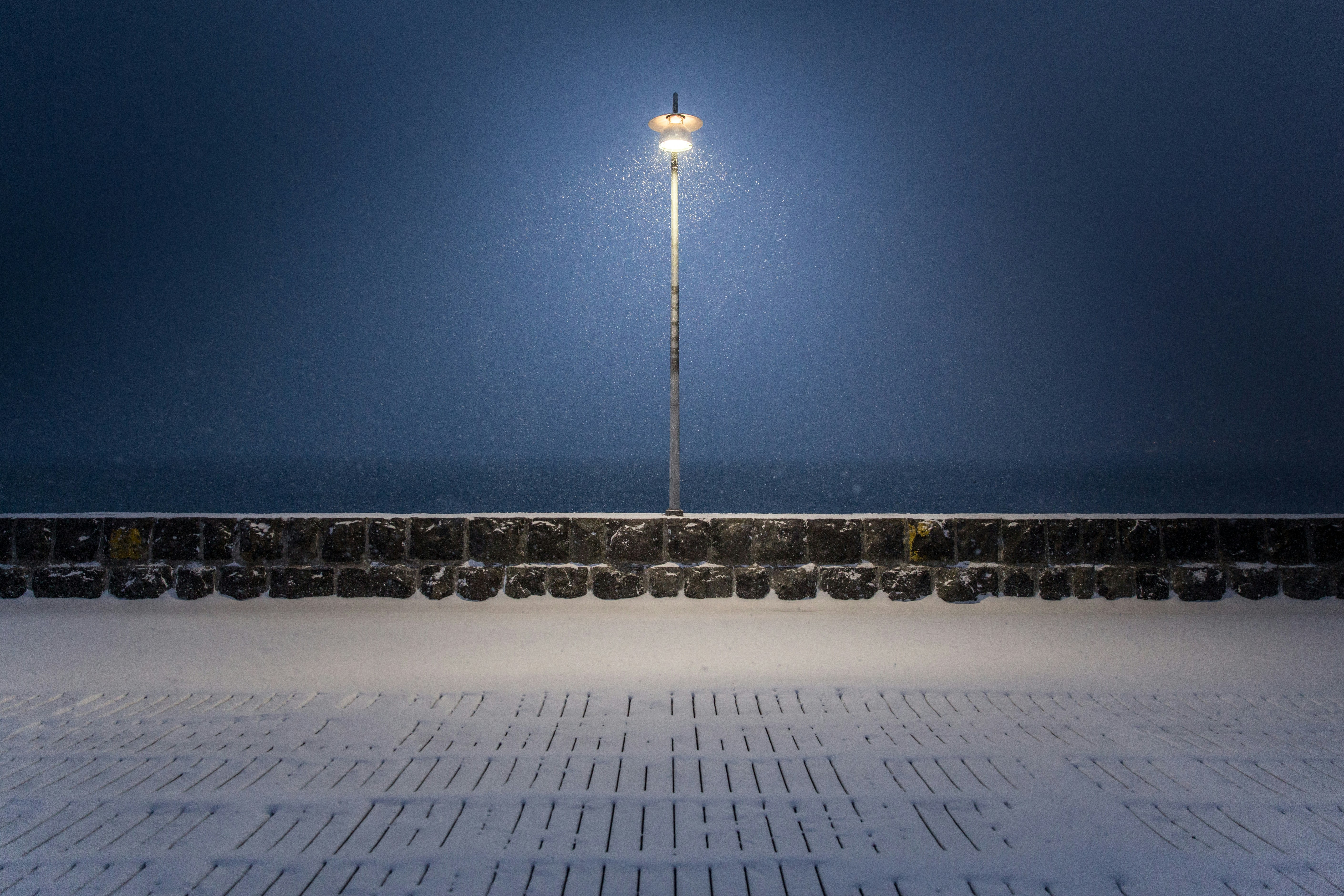 Midnight Lantern on a Snow-Dusted Sea Wall