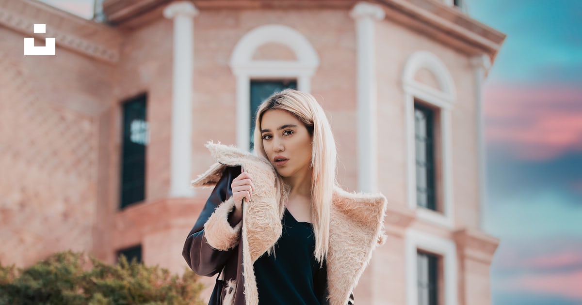 昼間に灰色のコンクリート舗装の上に立つ黒いコートと茶色のブーツを着た女性の写真 Unsplashの女の子の無料画像