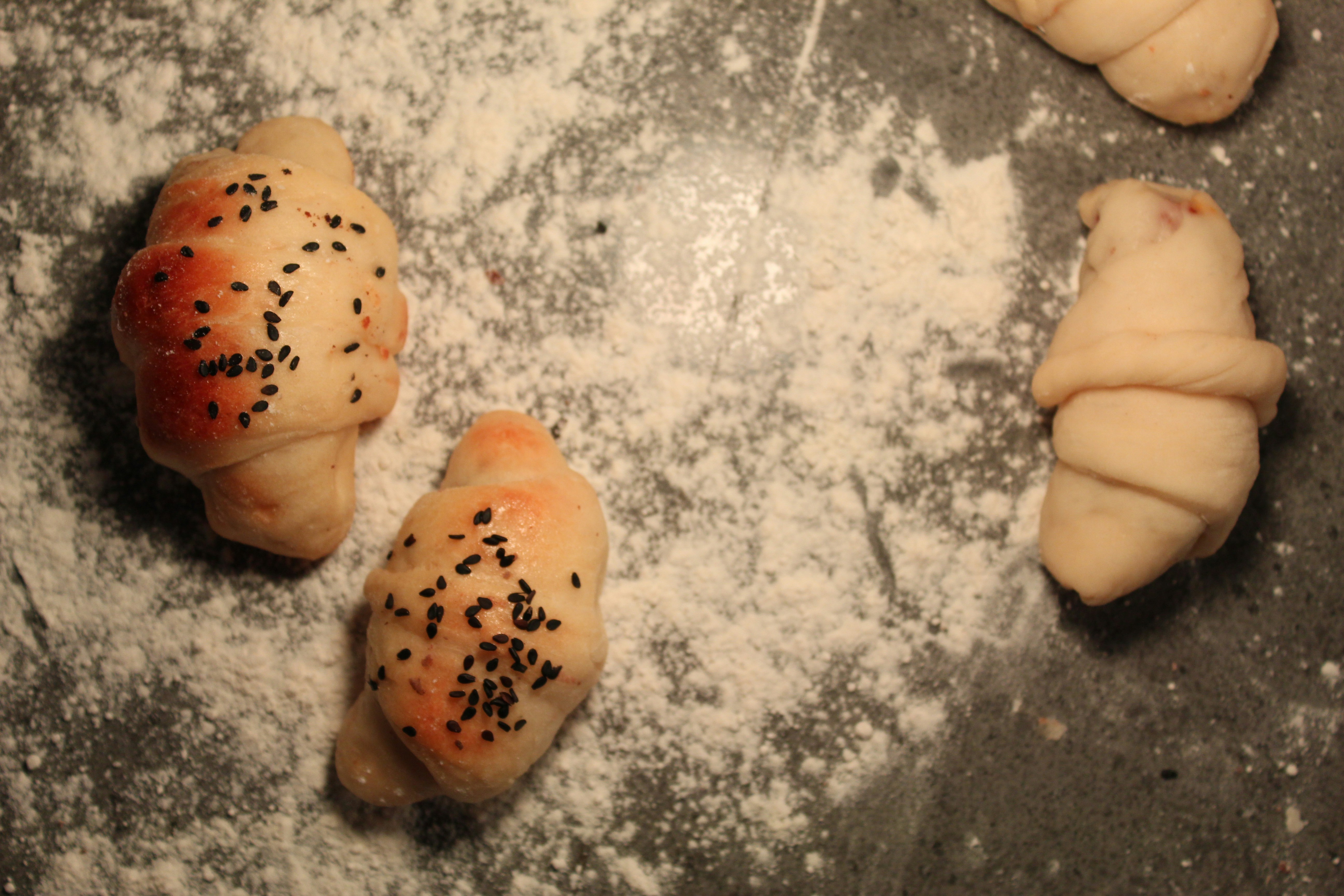 Freshly shaped croissants dusted with flour on a baking surface, showcasing intricate details and textures.