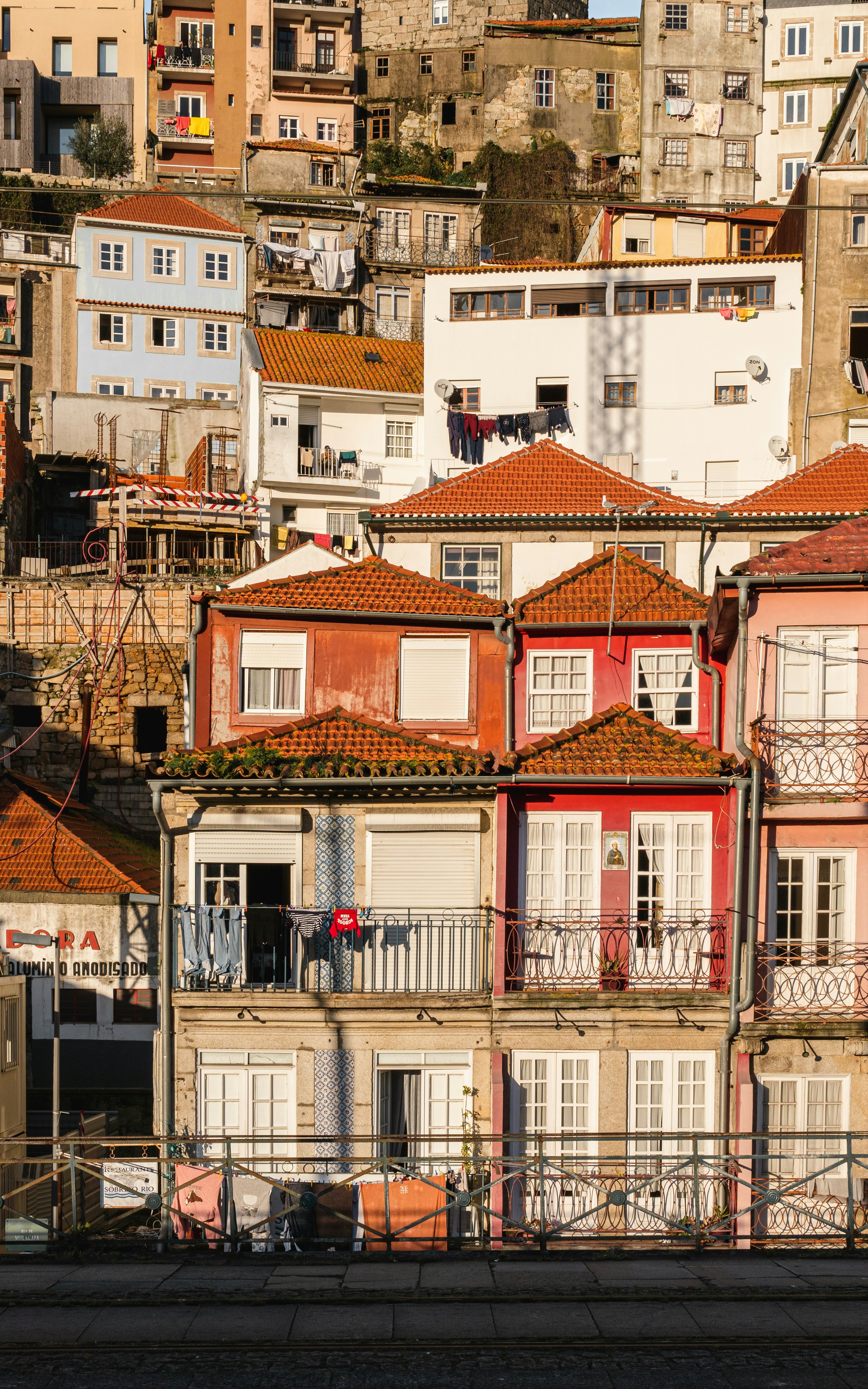 Colorful buildings with terracotta roofs and laundry hanging on balconies, showcasing the vibrant life in Porto's urban landscape.