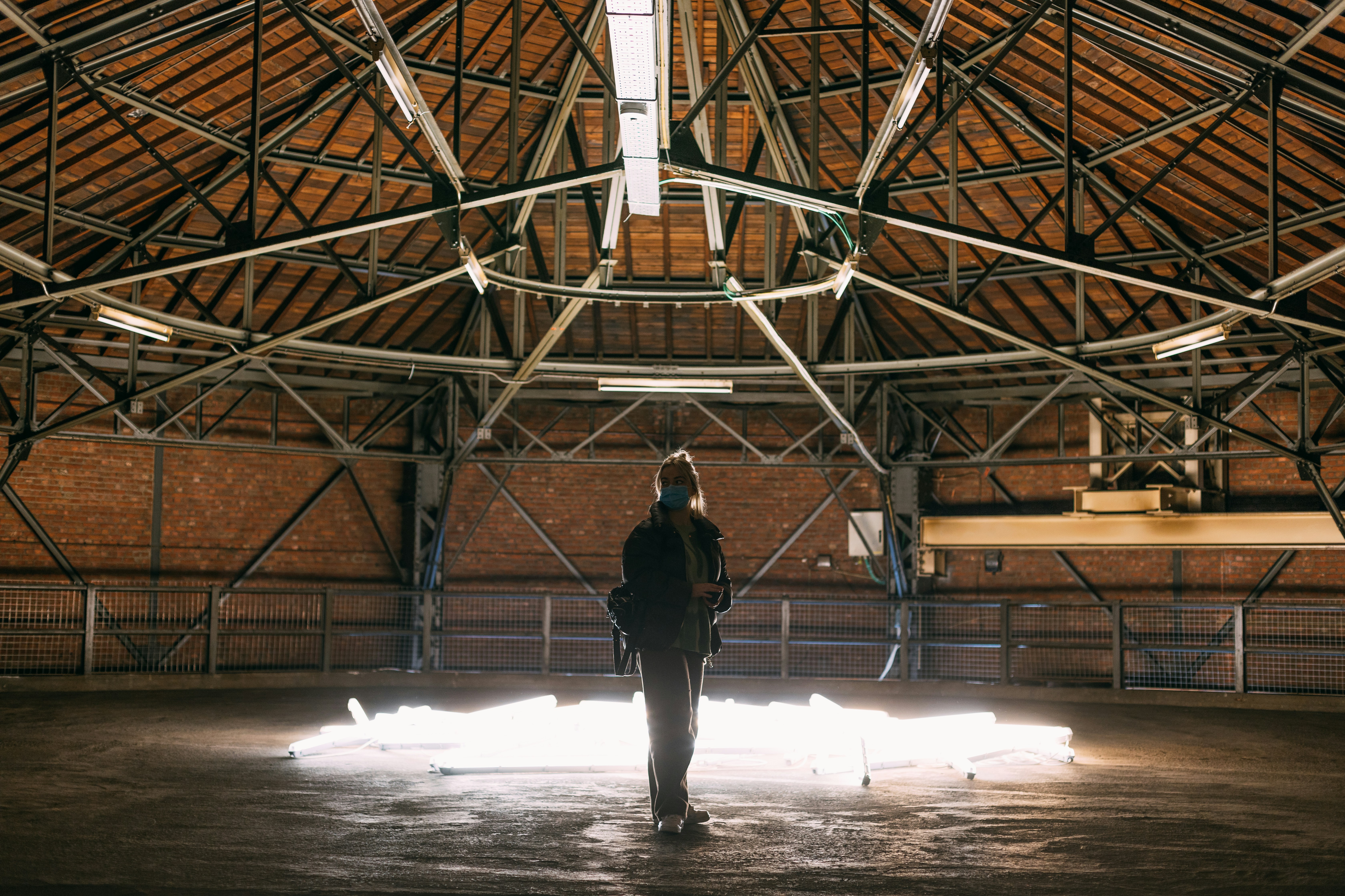 Backlit figure beneath a cathedral of trusses