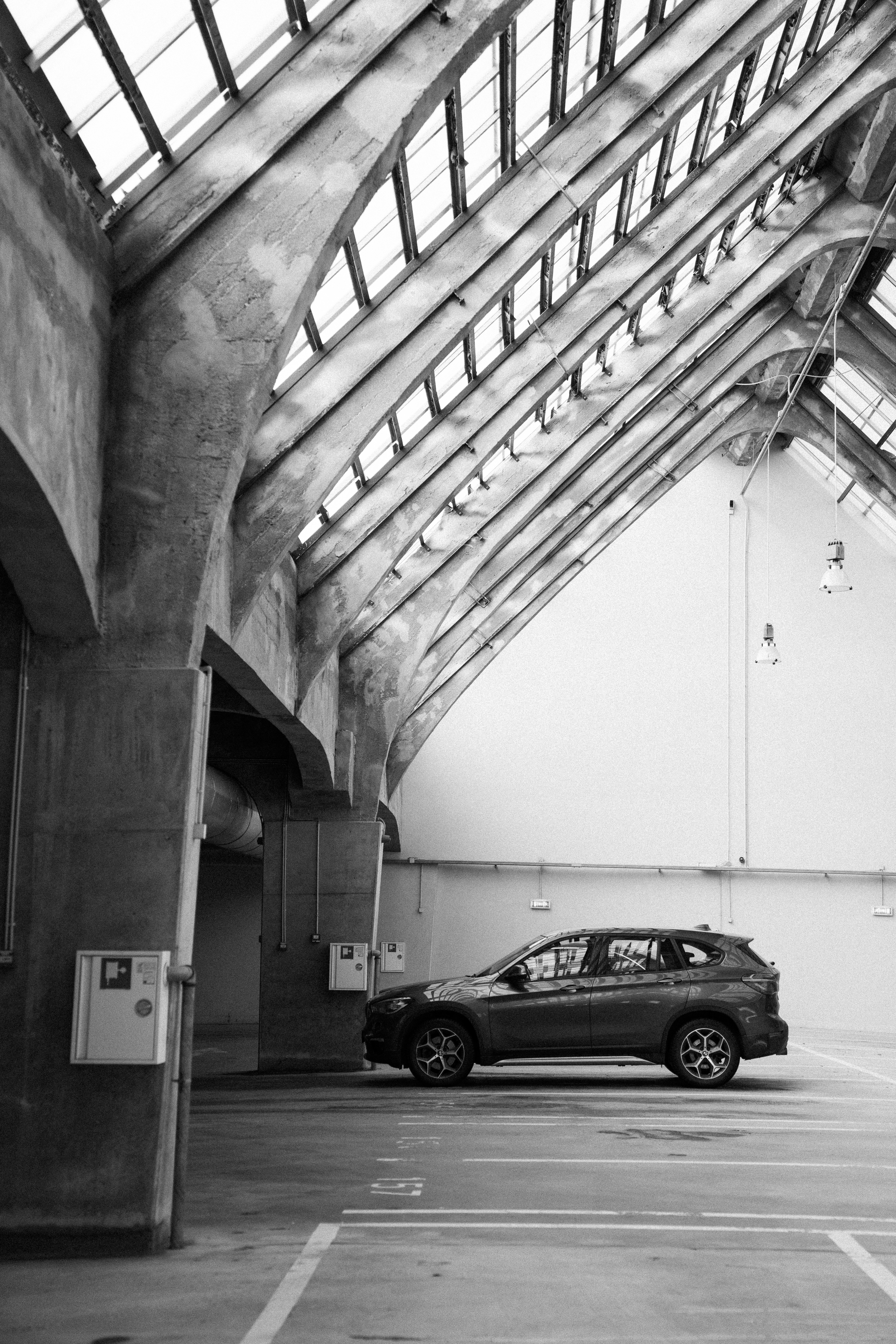 A sleek vehicle parked in a spacious, industrial garage featuring striking architectural lines and natural light filtering through skylights.