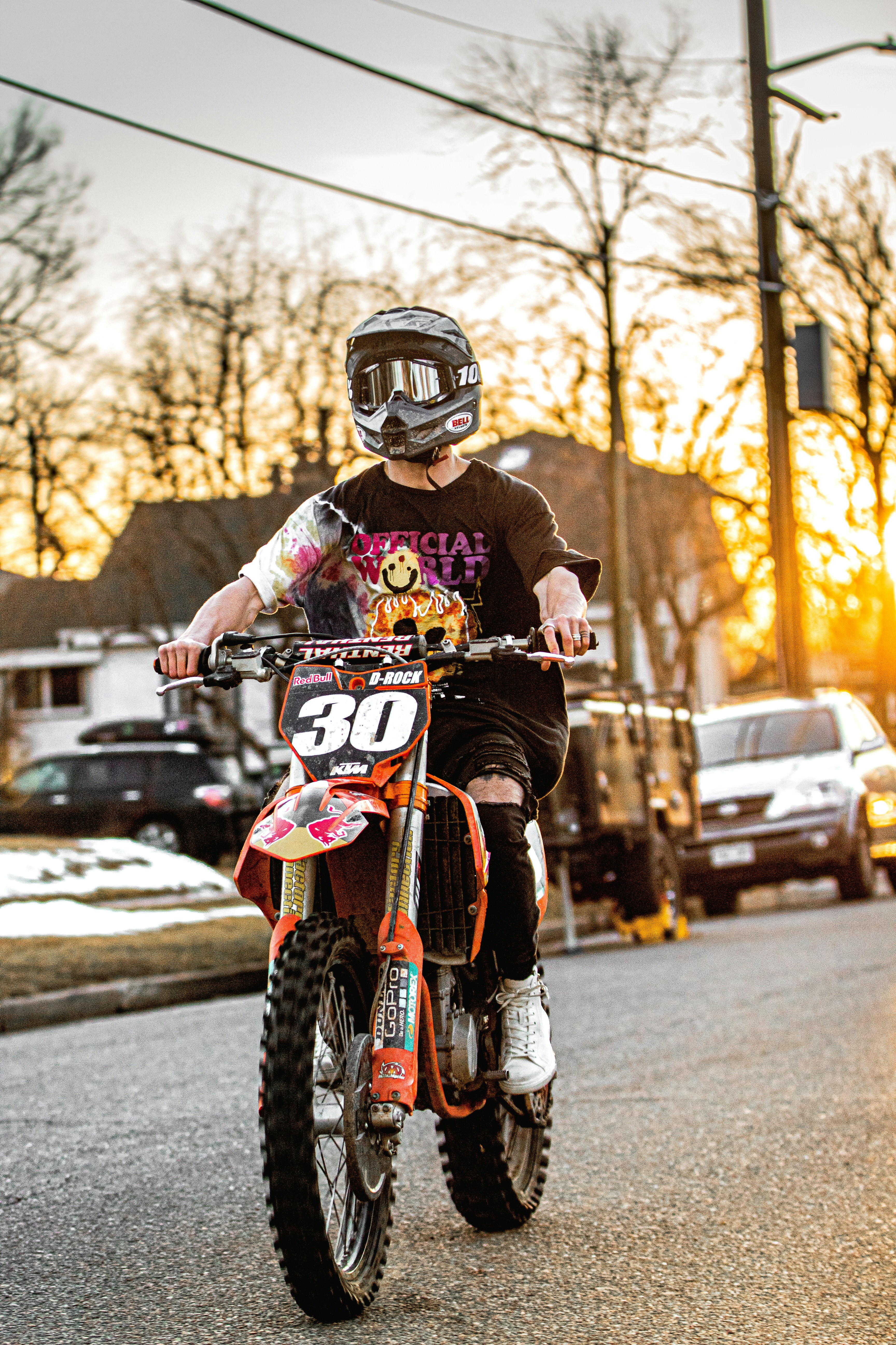 Dusk Dash: Orange Motocross Rider Cruising a Quiet Suburban Street at Sunset