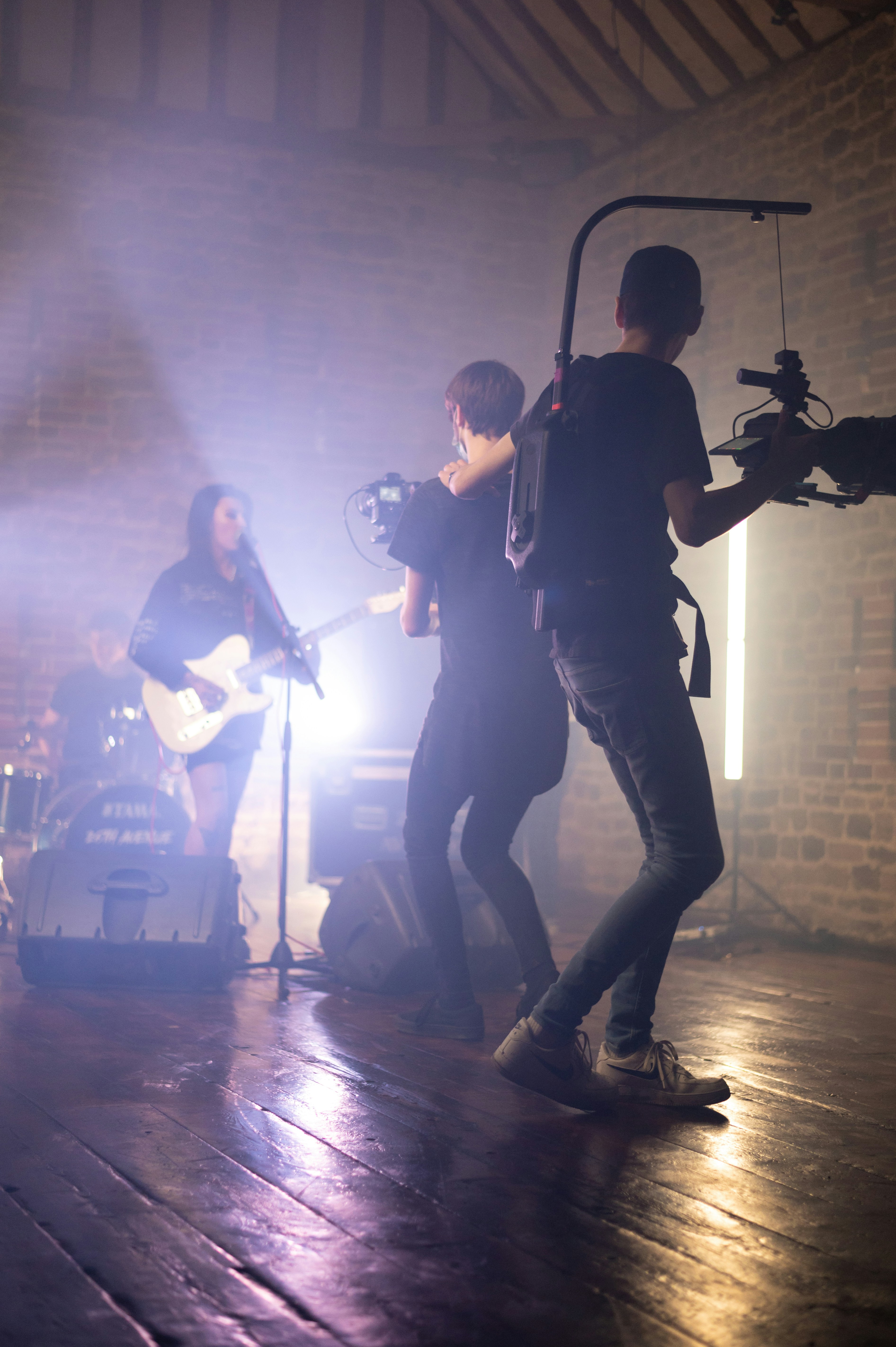 Energetic Side Stage: A Guitarist and Camera Operator Capture a Night-time Jam