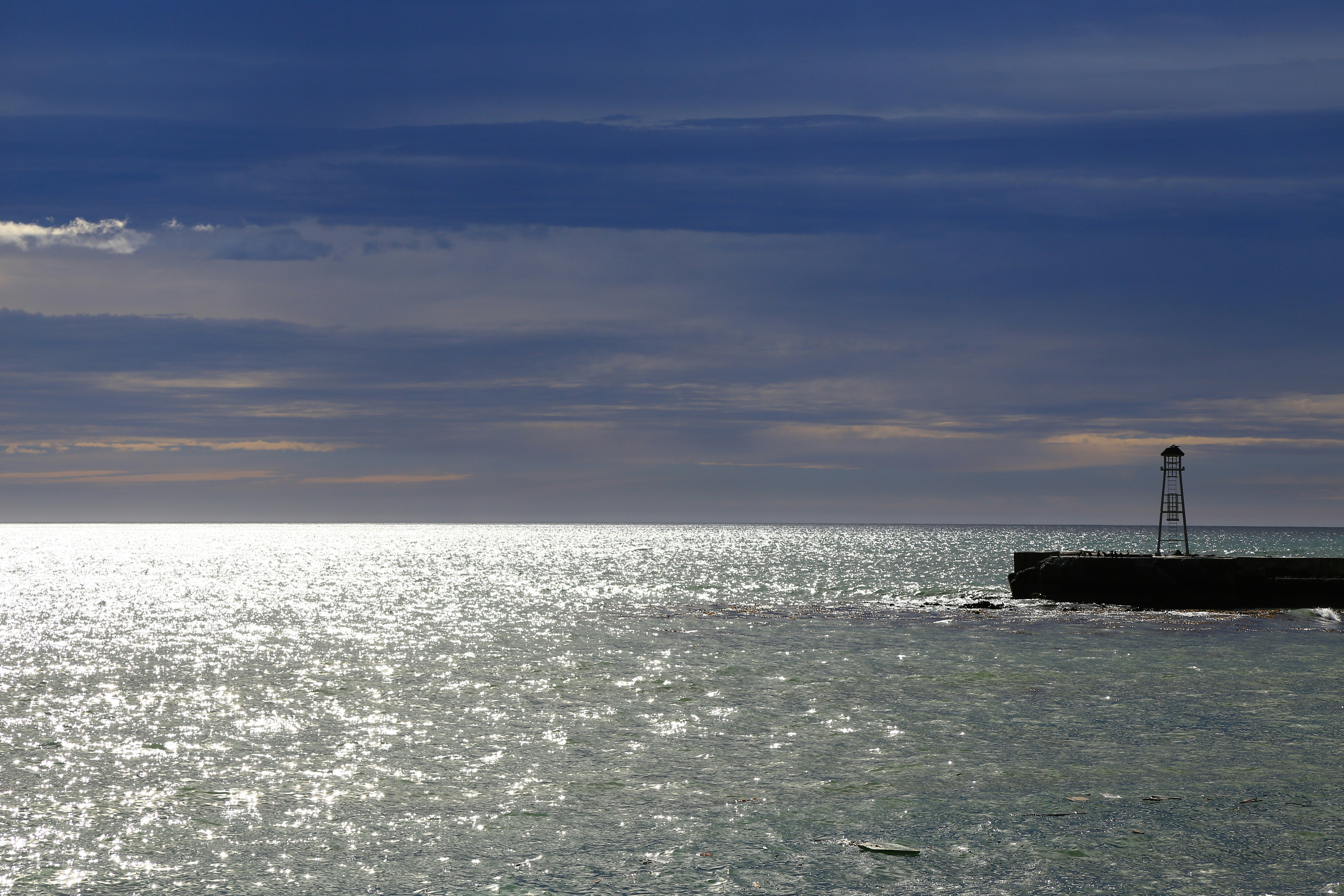 Lighthouse on the Edge: A Breakwater’s Silvery Horizon