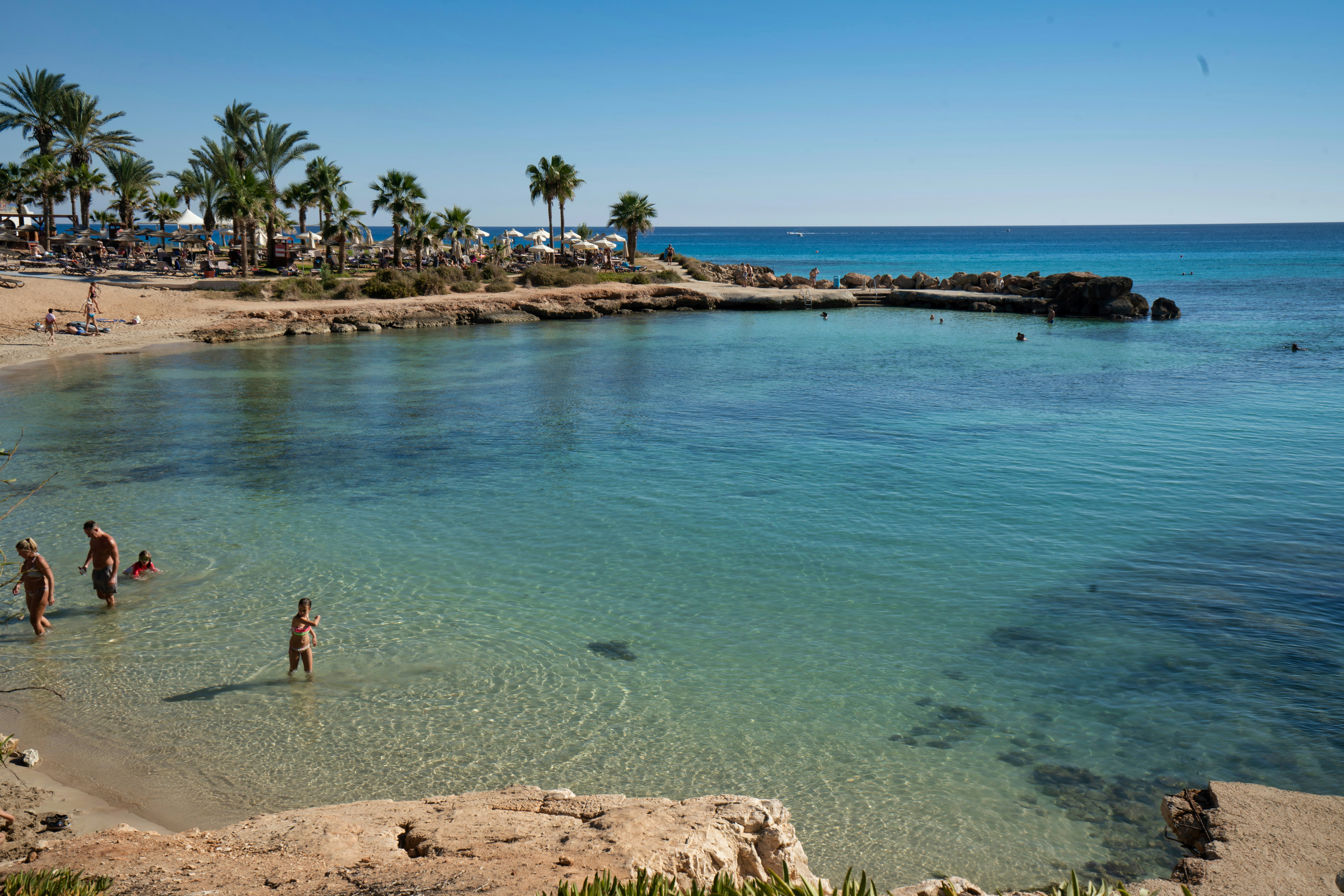 Picturesque oceanscape of Nissie Beach in Cyprus. | people swimming on beach during daytime
