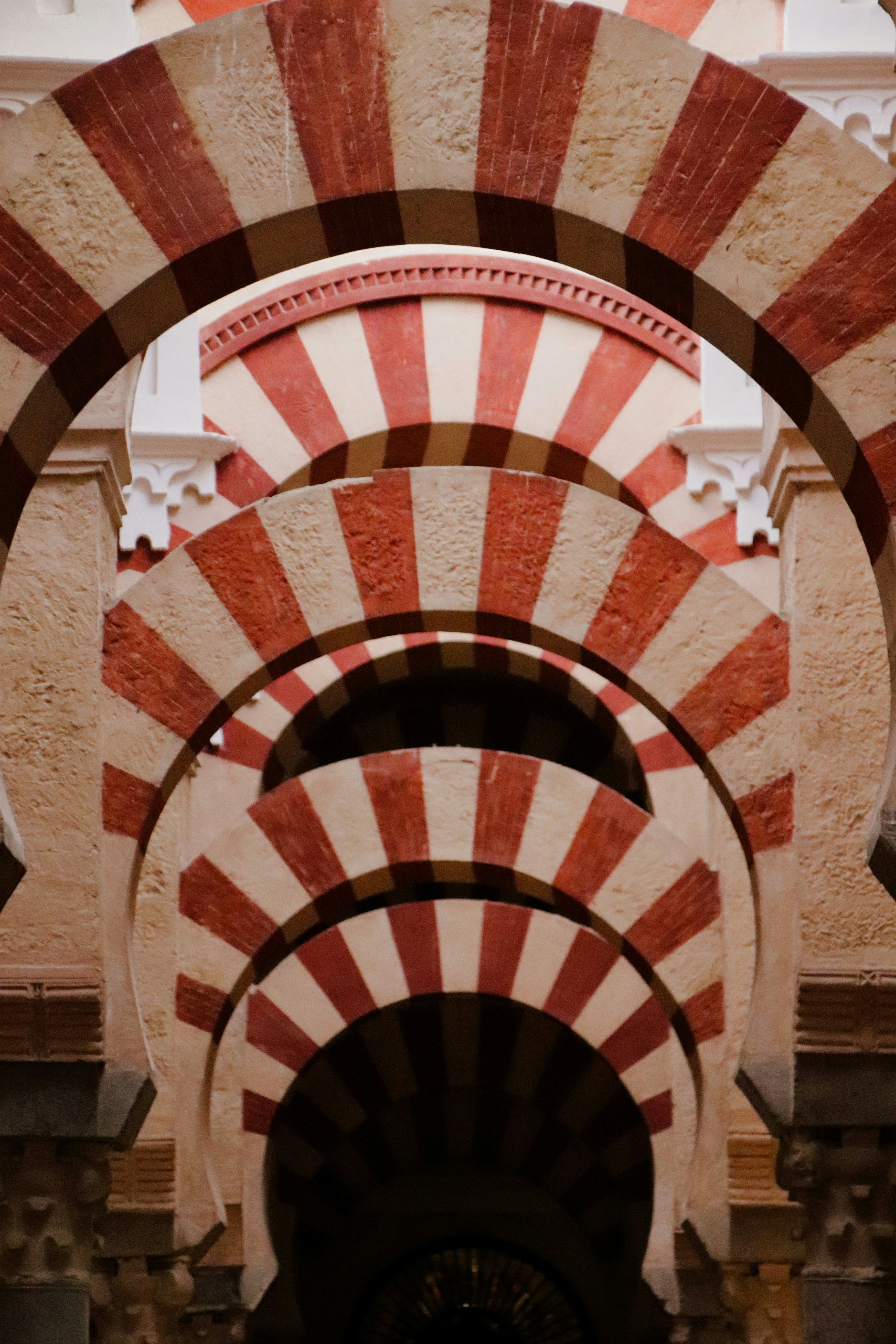 Intricate arches adorned with alternating red and white stripes create a mesmerizing pattern in a historic corridor.