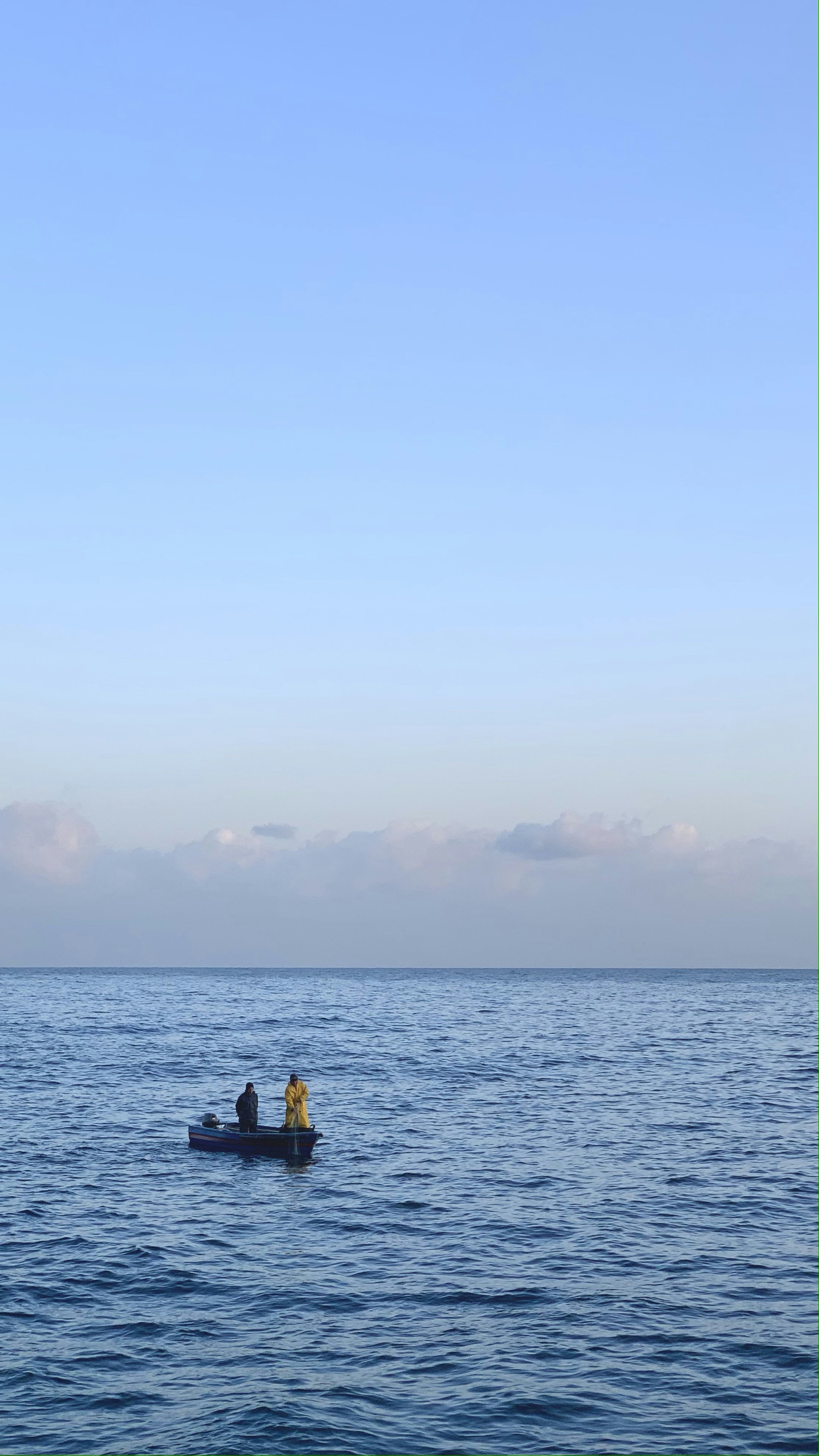 Two Figures in a Small Boat Across a Quiet Blue Sea