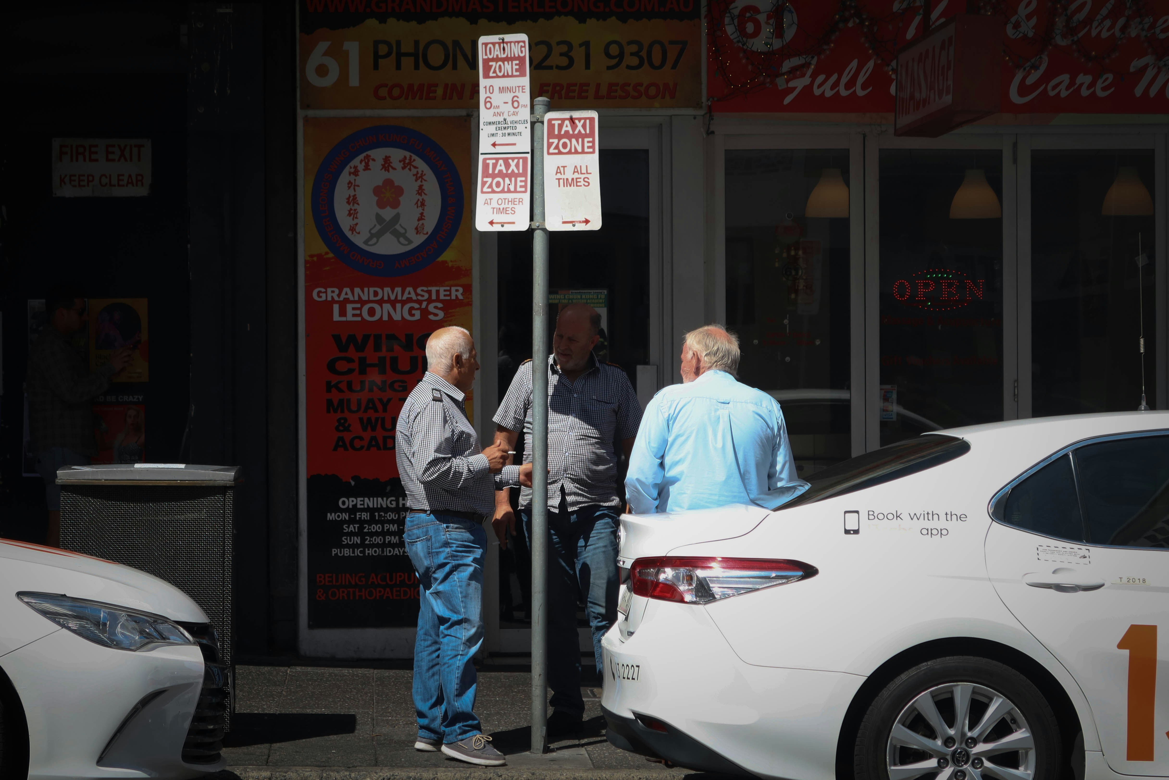 Corner Summit at the Signpost: Three Men by the Taxi