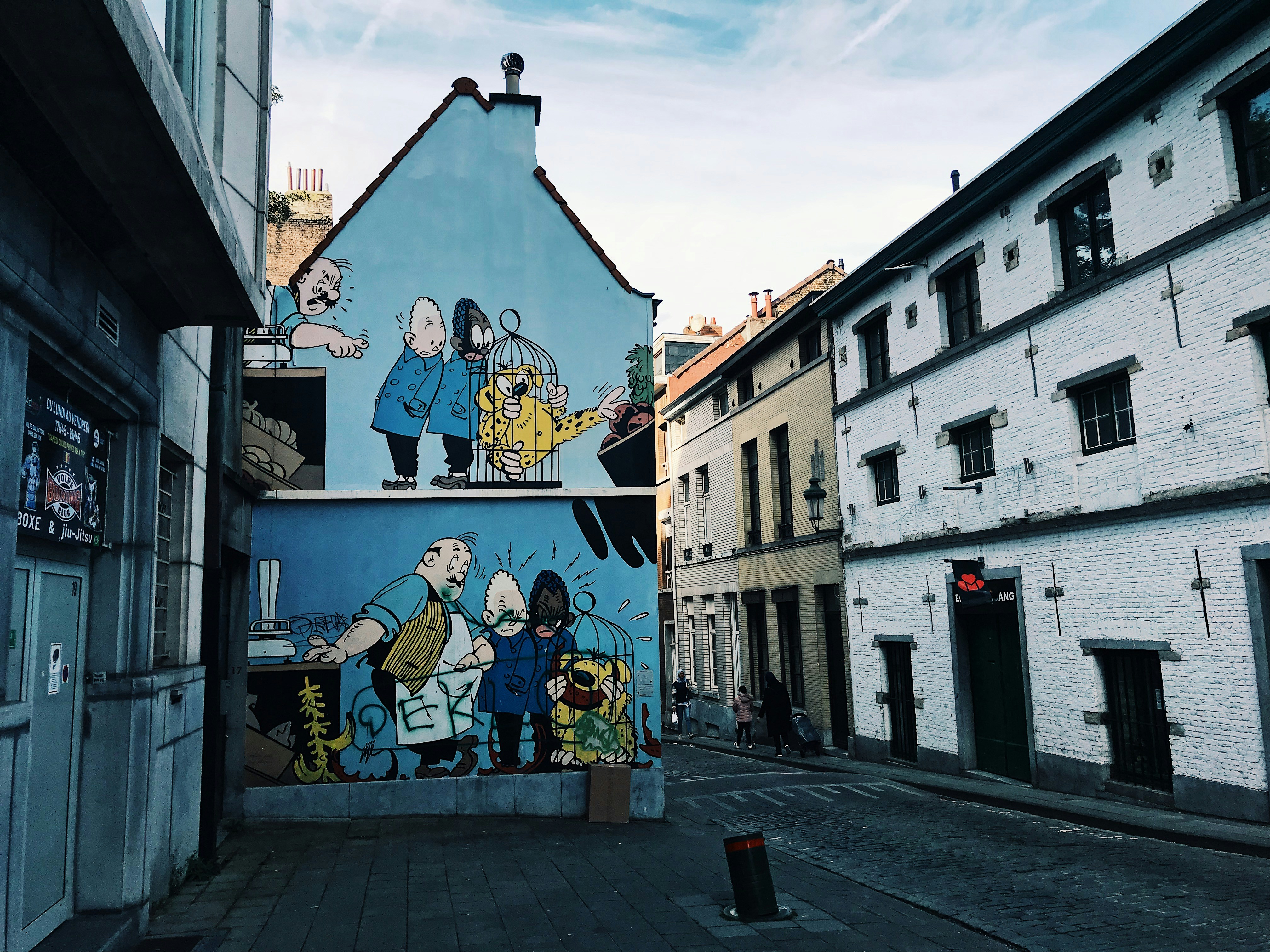 Colorful mural depicting animated characters interacting in a lively street scene. The artwork adds vibrancy to the urban landscape.