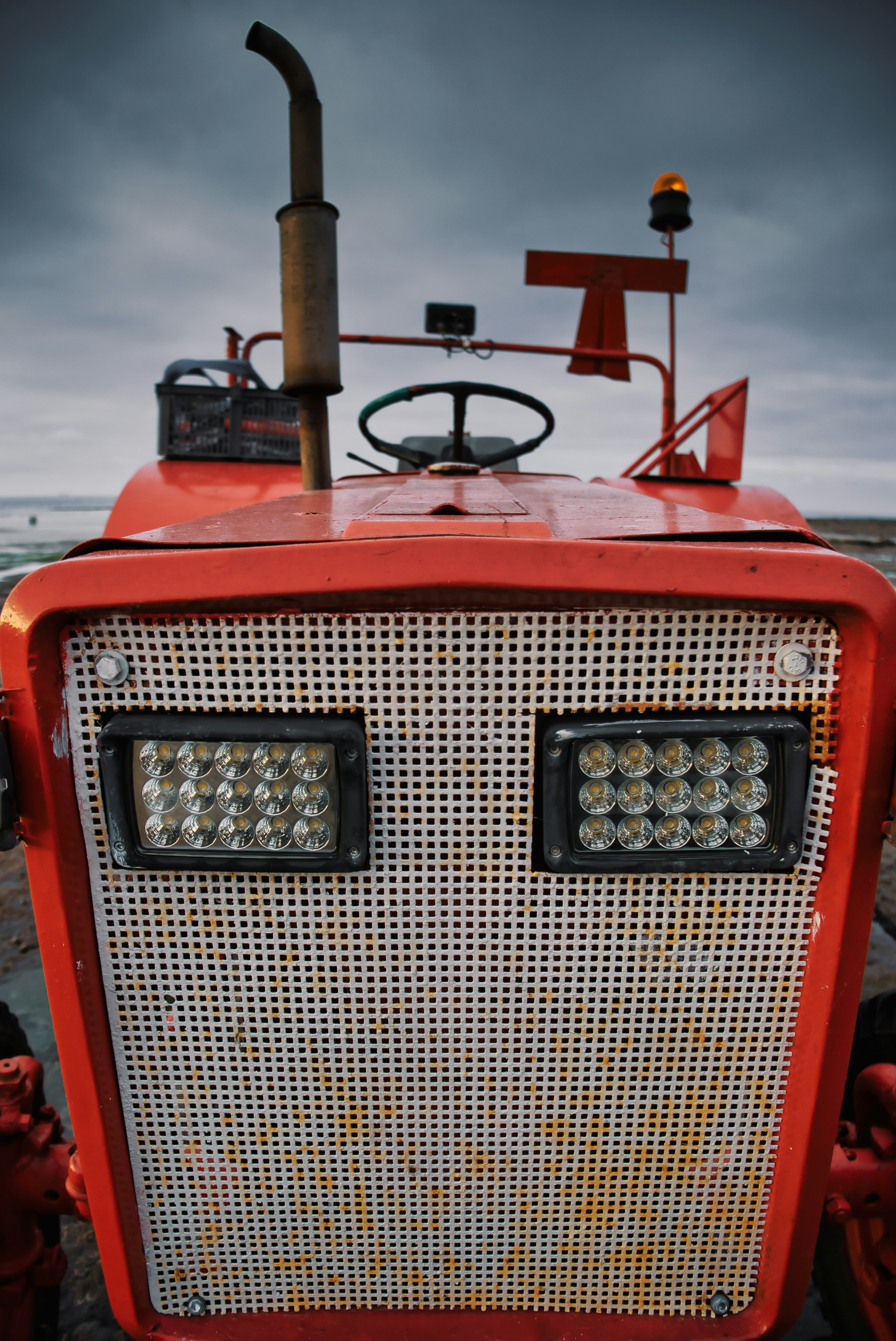 Crimson Front Grille: A Tracked Tractor’s Grit under Stormy Skies