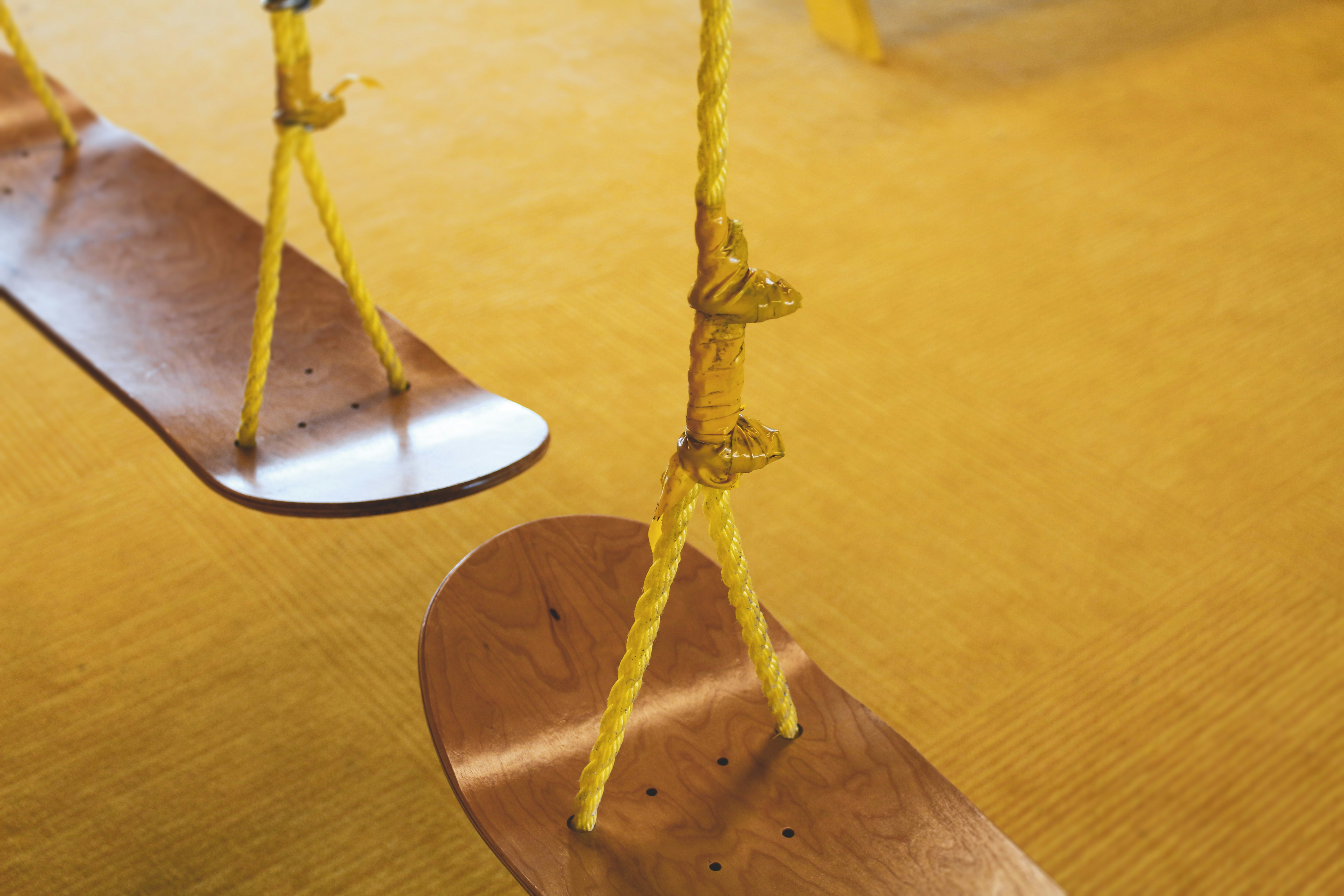 Rope-Lined Quiet: Yellow Ropes Framing Wooden Swings on a Golden Floor
