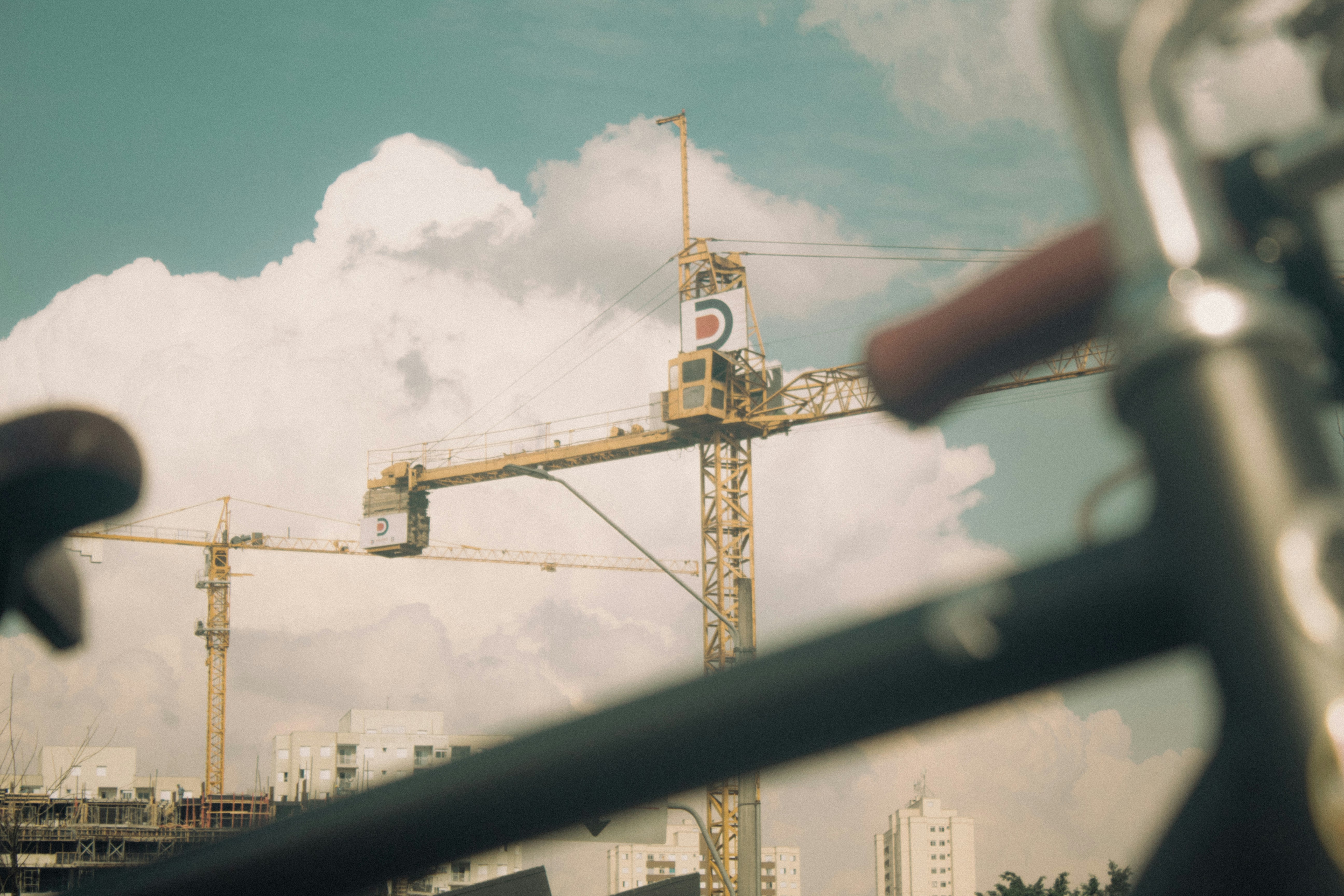 Skyward Cranes Framing a Teal-Cloud Cityscape