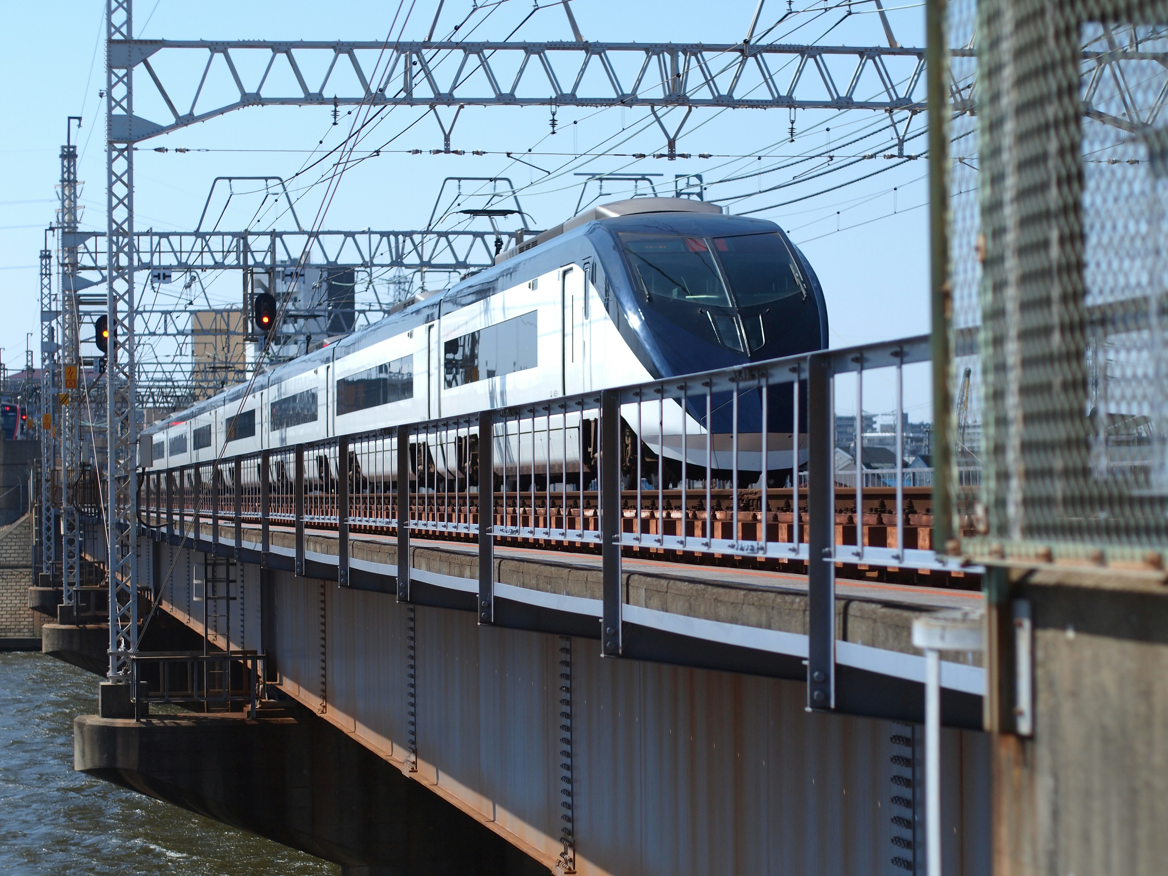 High-speed train traveling across an elevated bridge under clear skies.