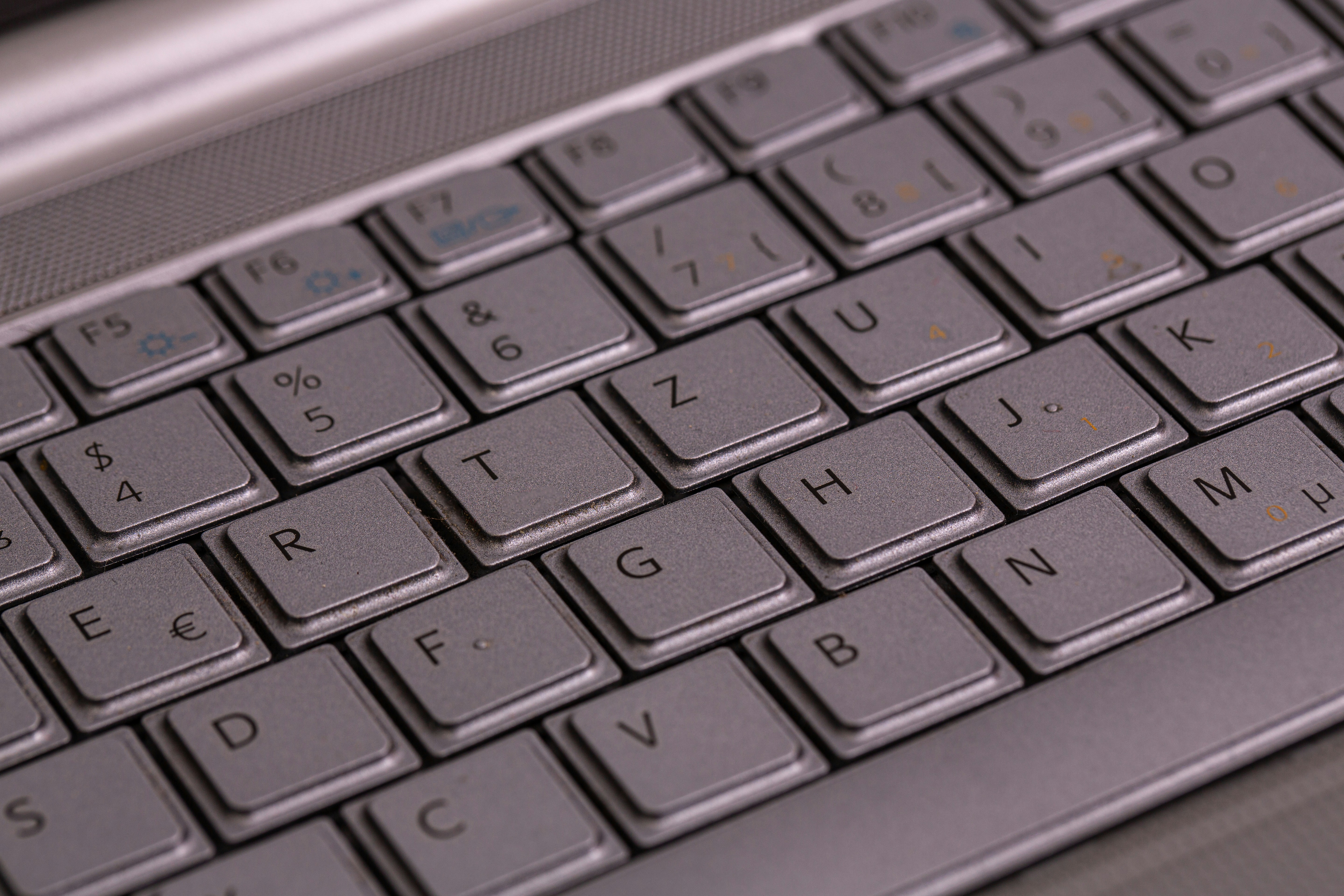 Close-up of a laptop keyboard showcasing worn keys and intricate textures, emphasizing the everyday tools of digital communication.