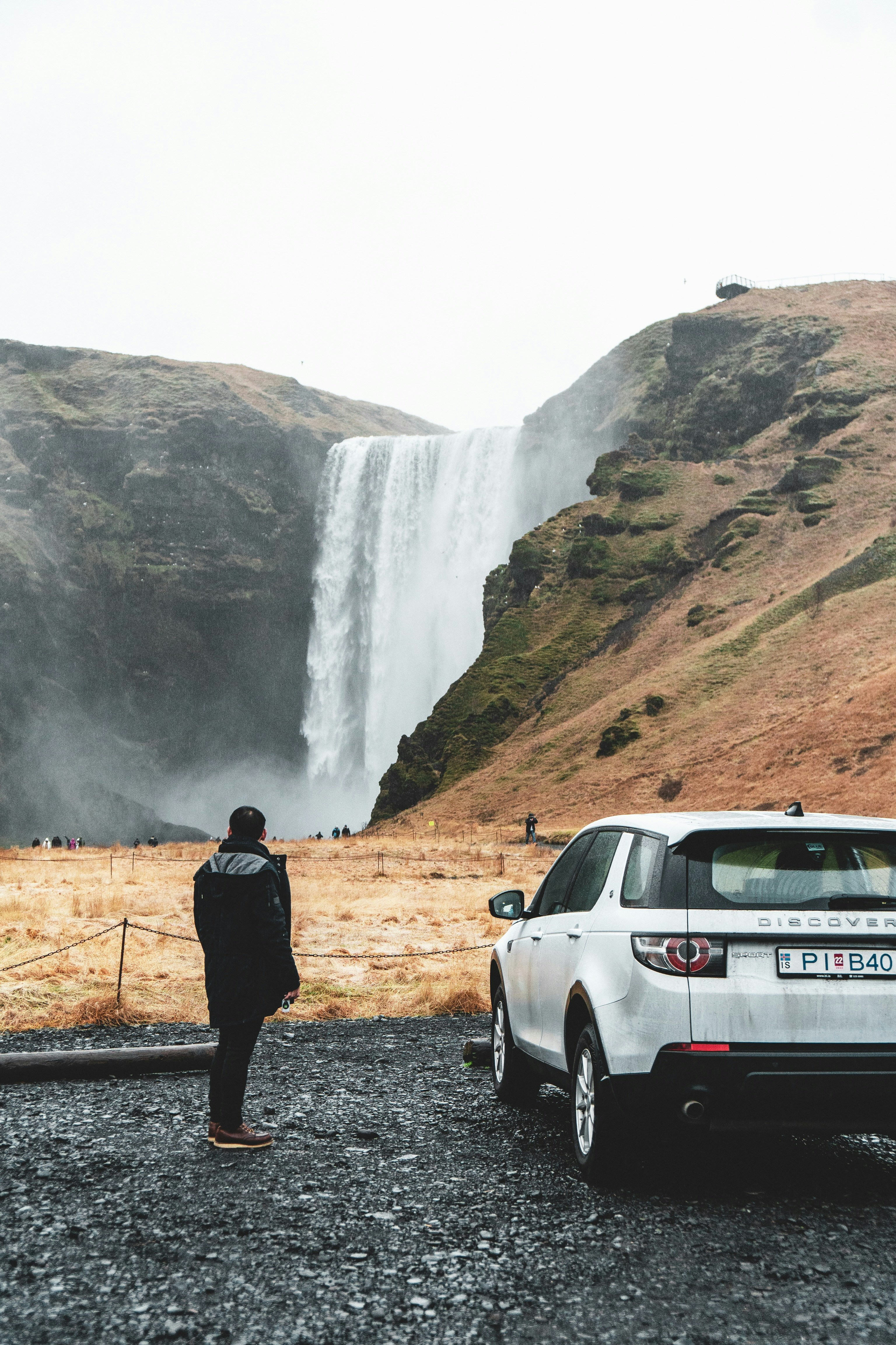 woman in black coat standing near white car