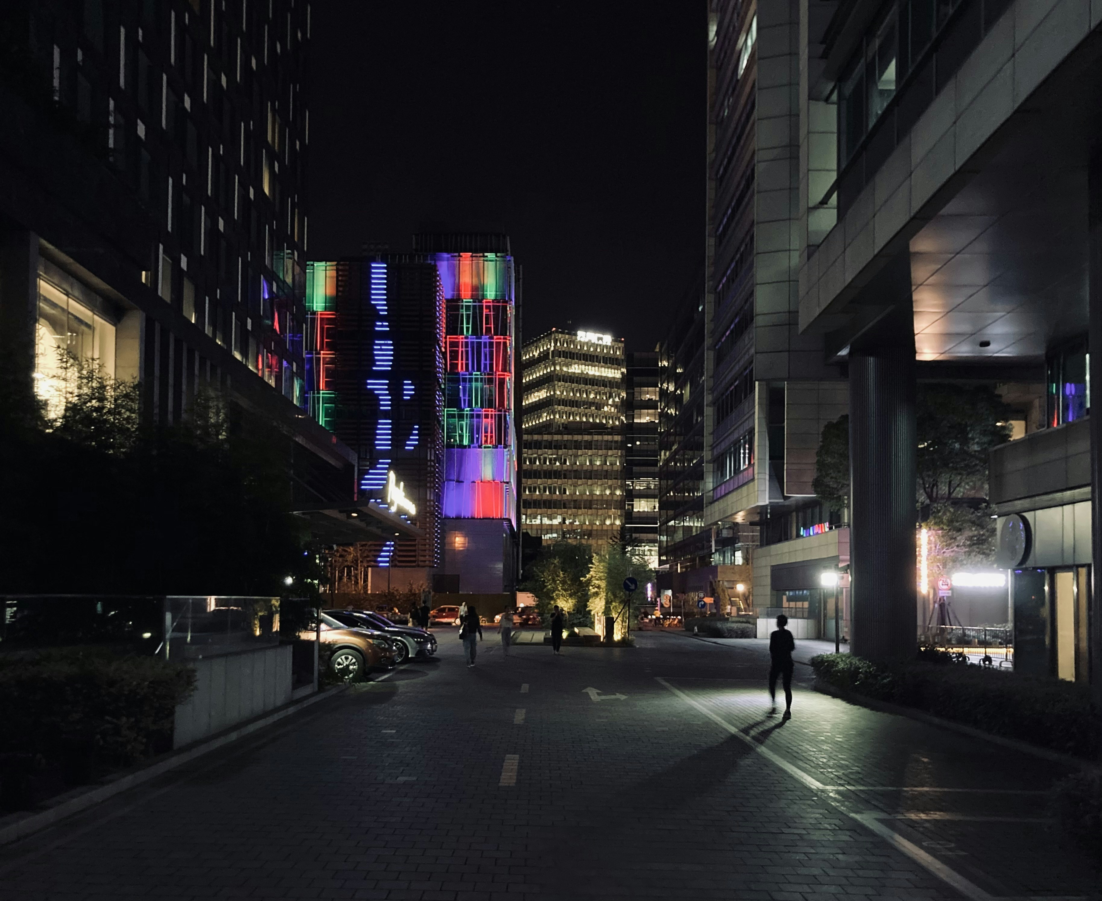 People walking on sidewalk near high rise buildings during night time ...