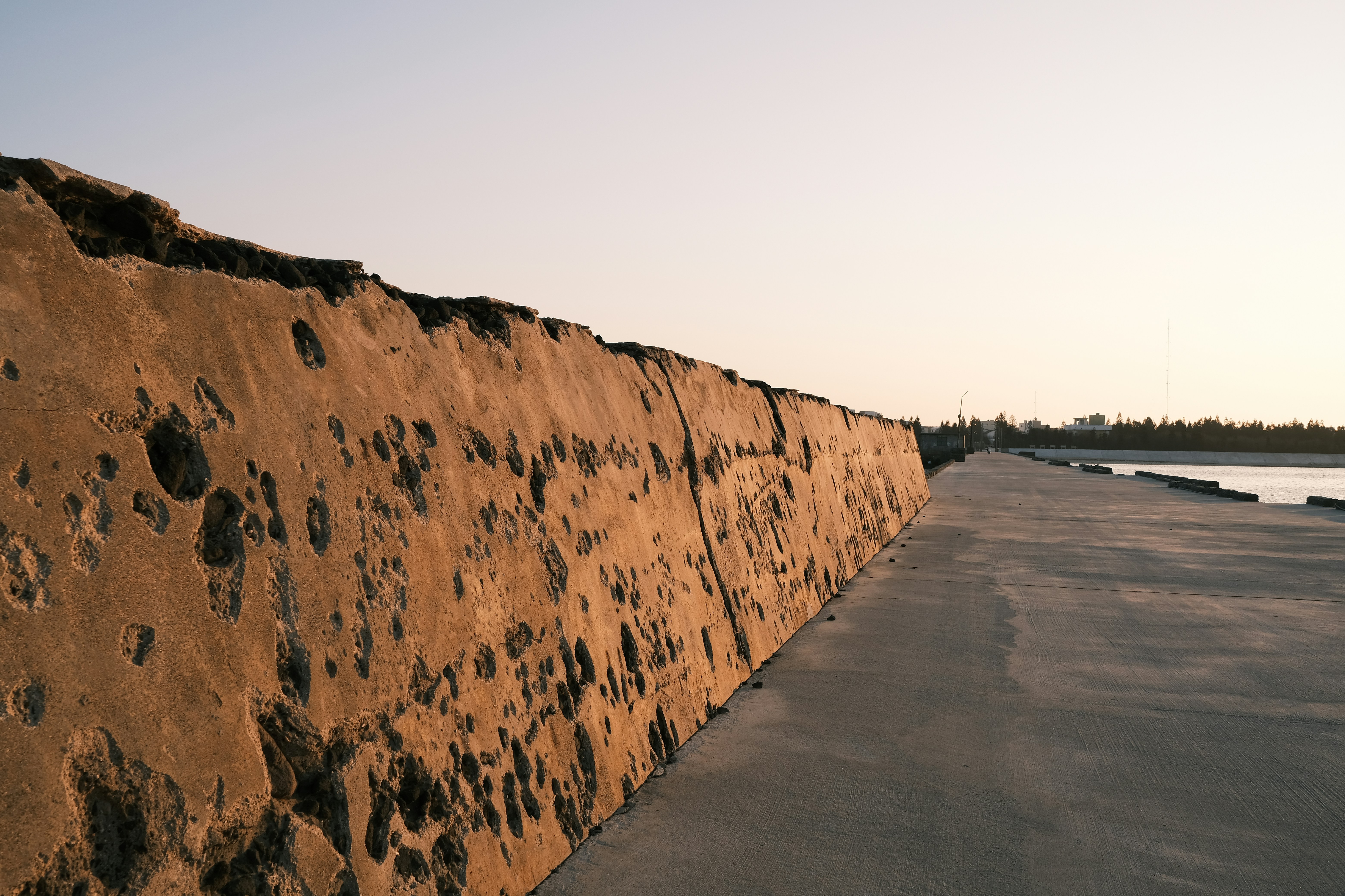 Sunlit Boundary: A Weathered Seawall Reaching Toward the Quiet Horizon