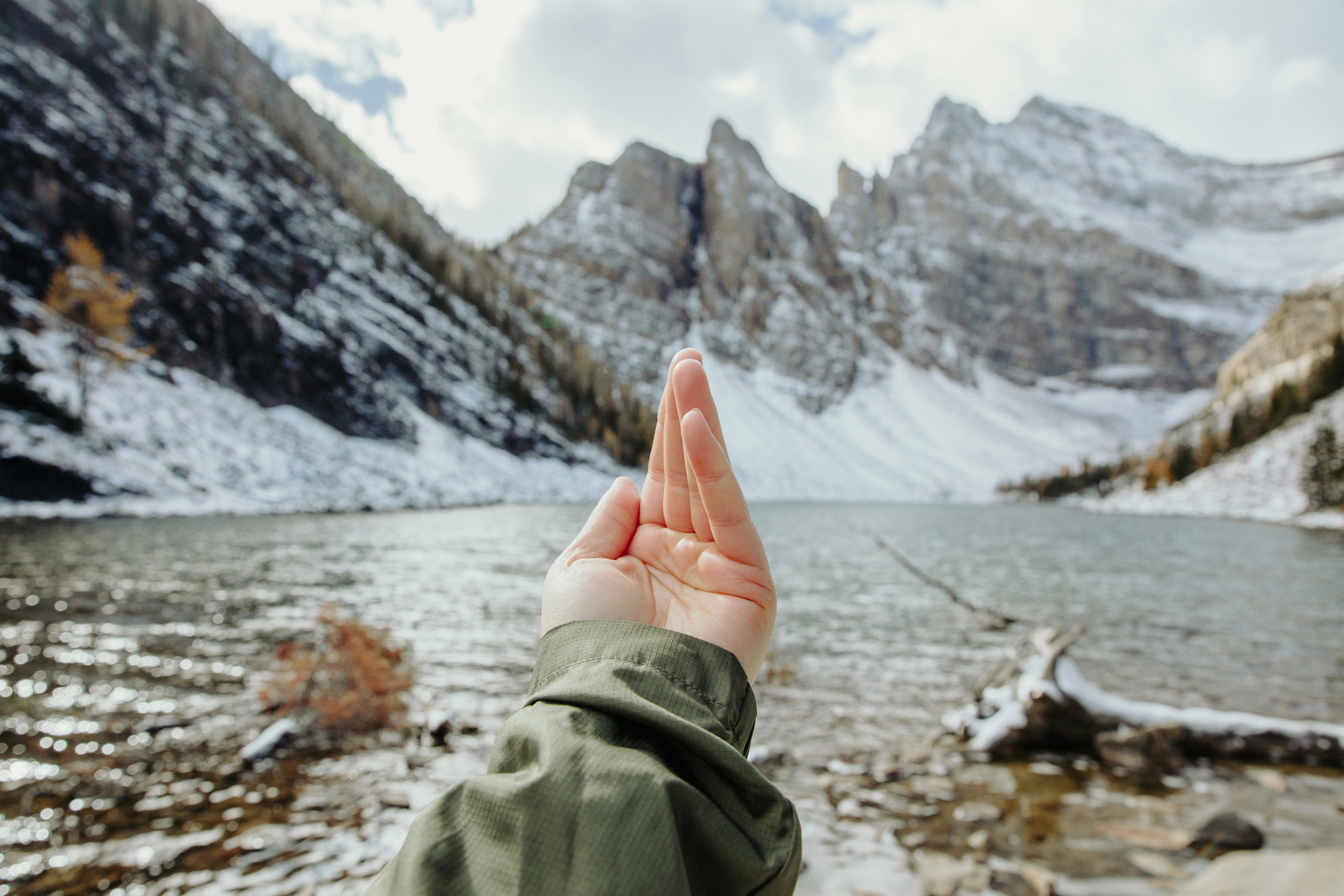 Hand gesture at the glacier-fed lake: a quiet foreground in a snowy canyon
