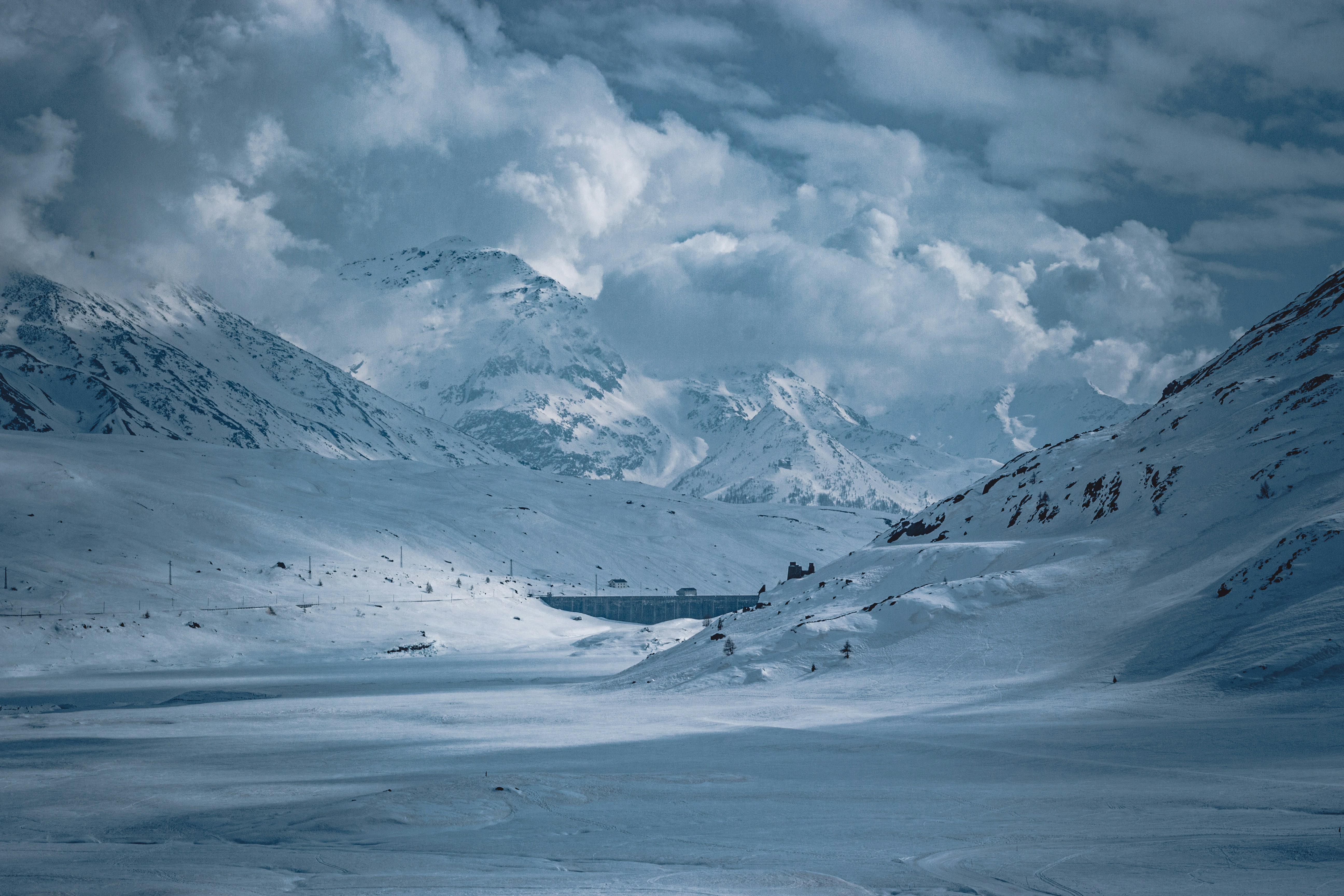 Snow-covered mountains stretch under dramatic clouds during daylight.