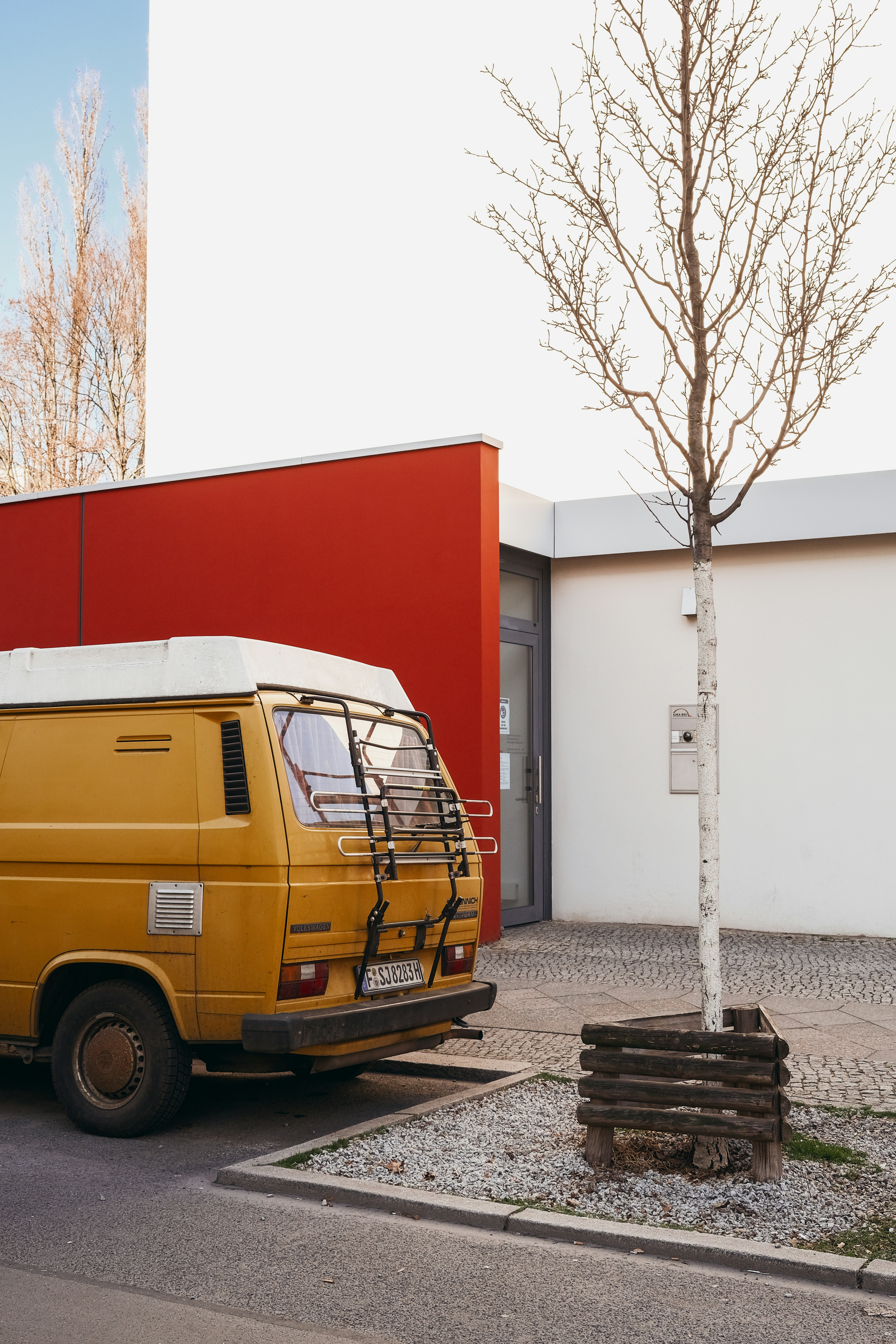 A retro volkswagon bus is parked in front of a red wall in Berlin, Germany.