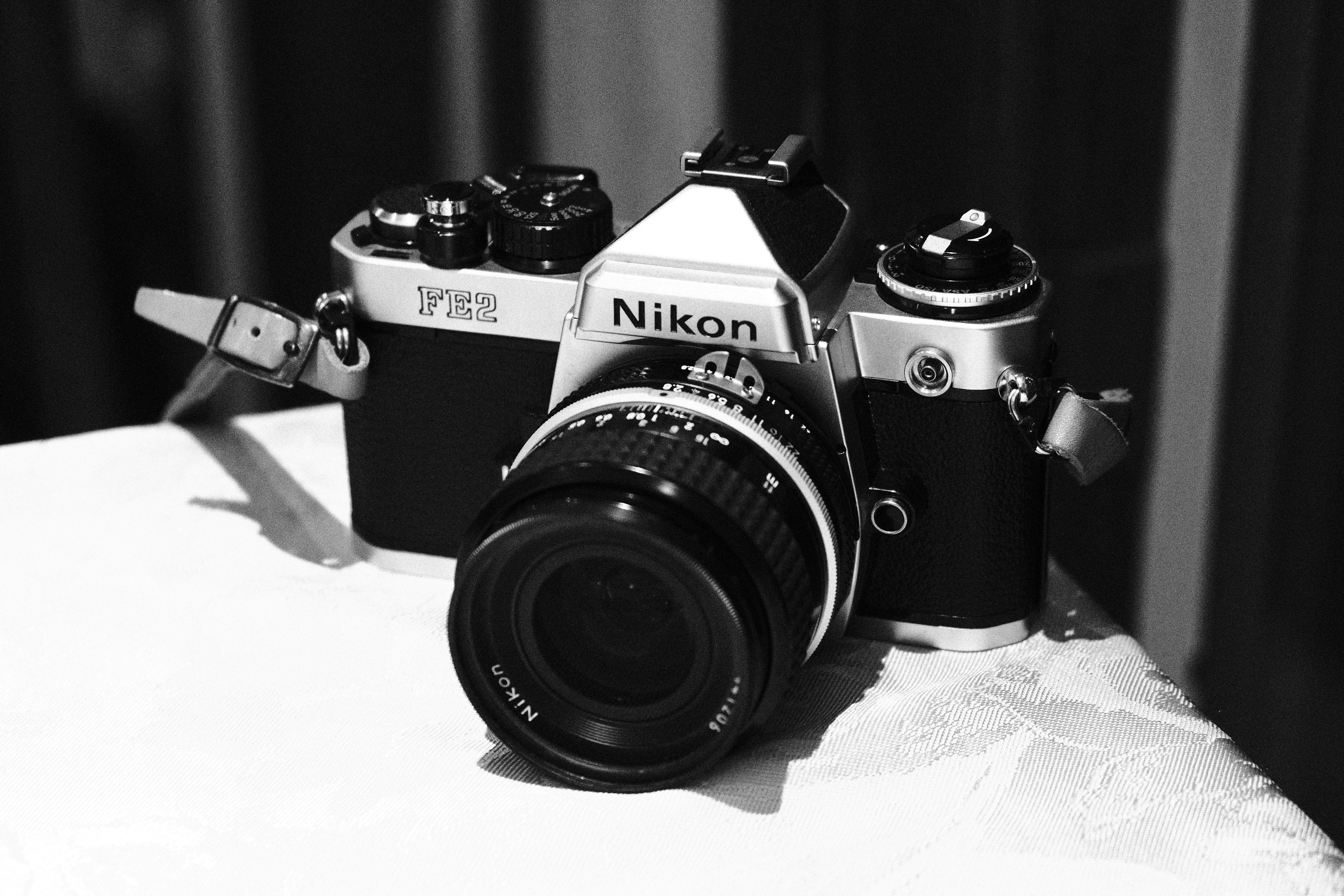 black and silver nikon dslr camera on white textile
