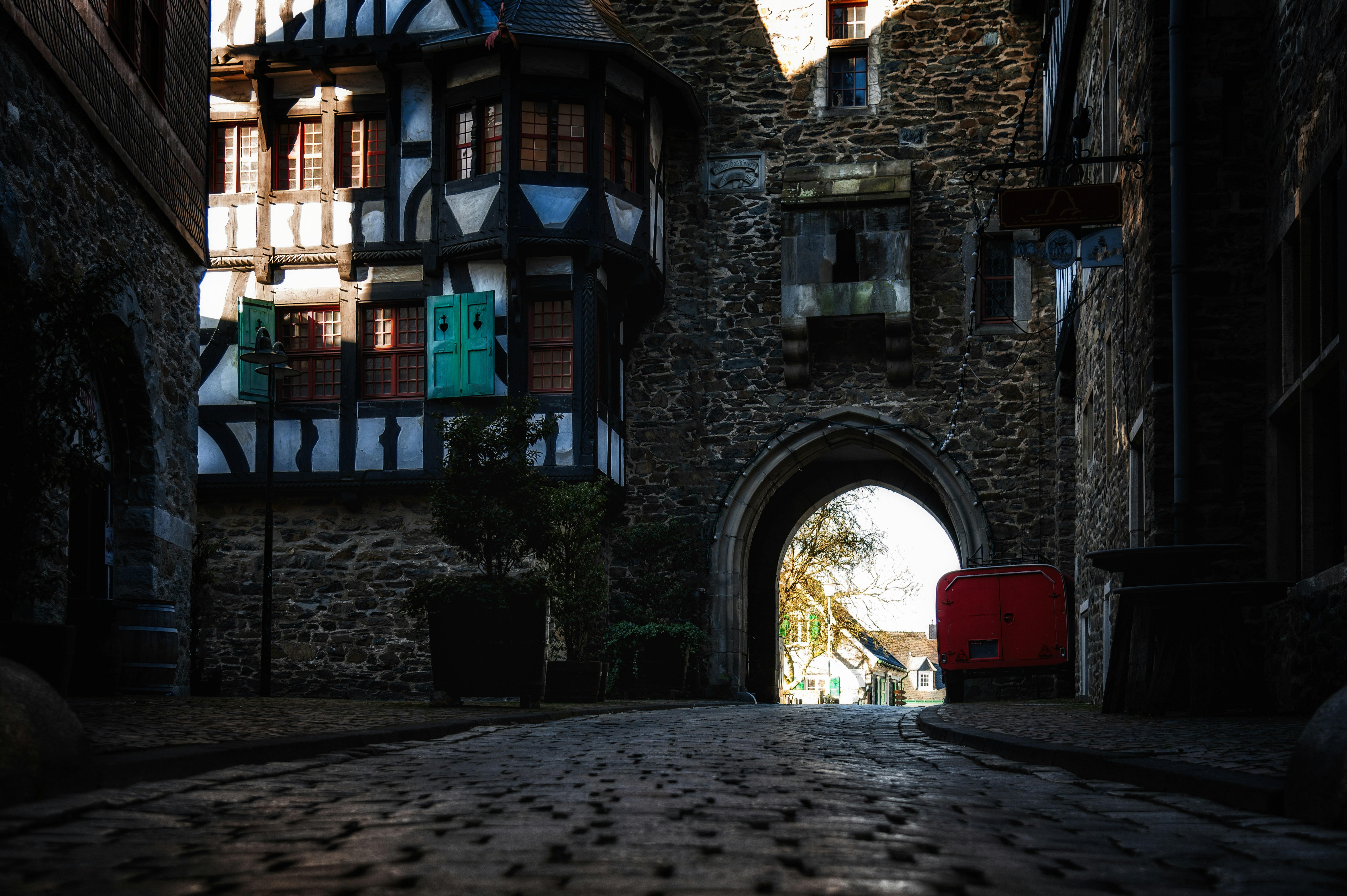Arched Gateway Framed by Tudor Facades: Cobblestones to Light