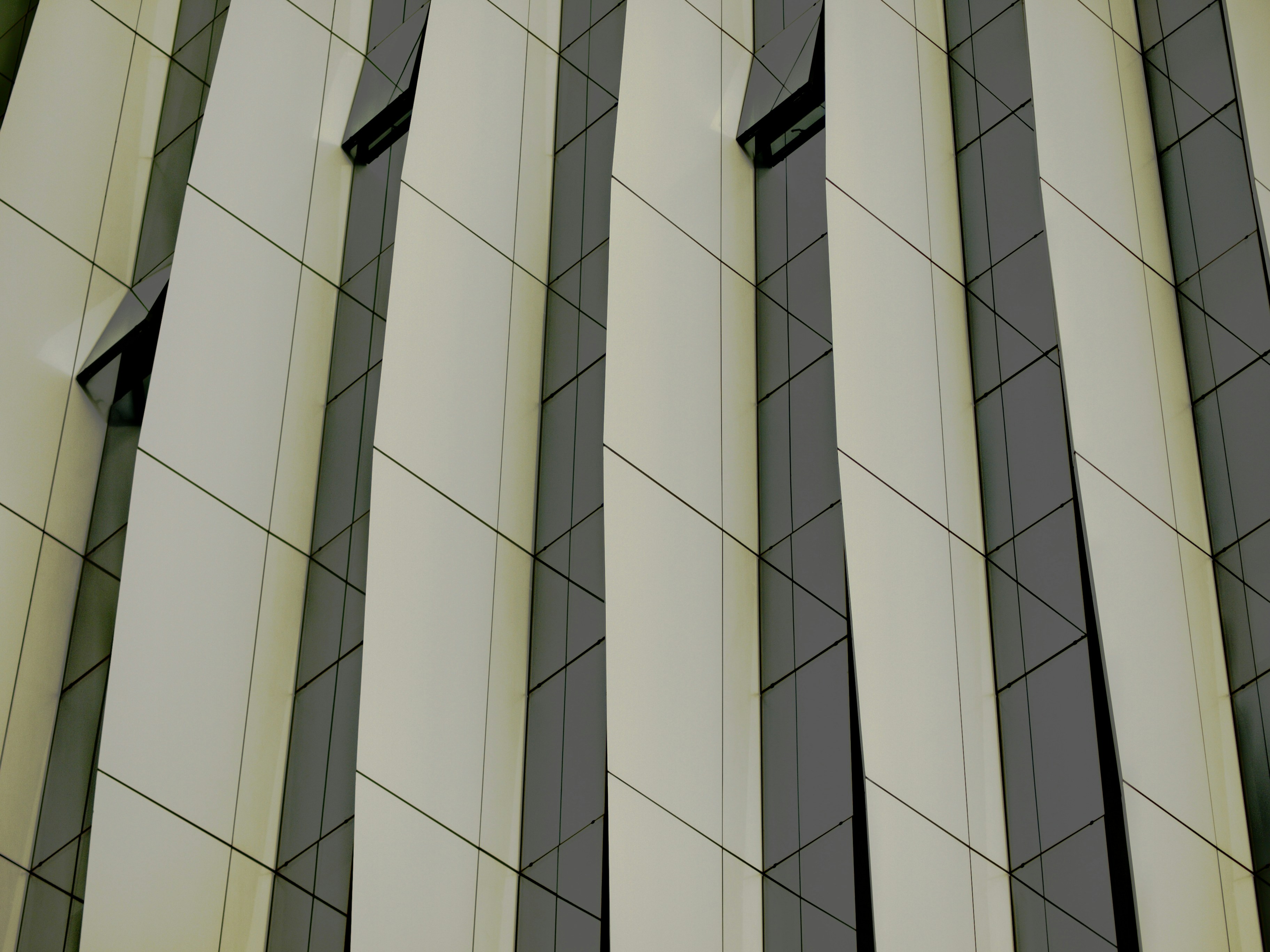 Architectural photography of a modern facade featuring tall beige and gray vertical slats arranged in a striking diagonal rhythm.