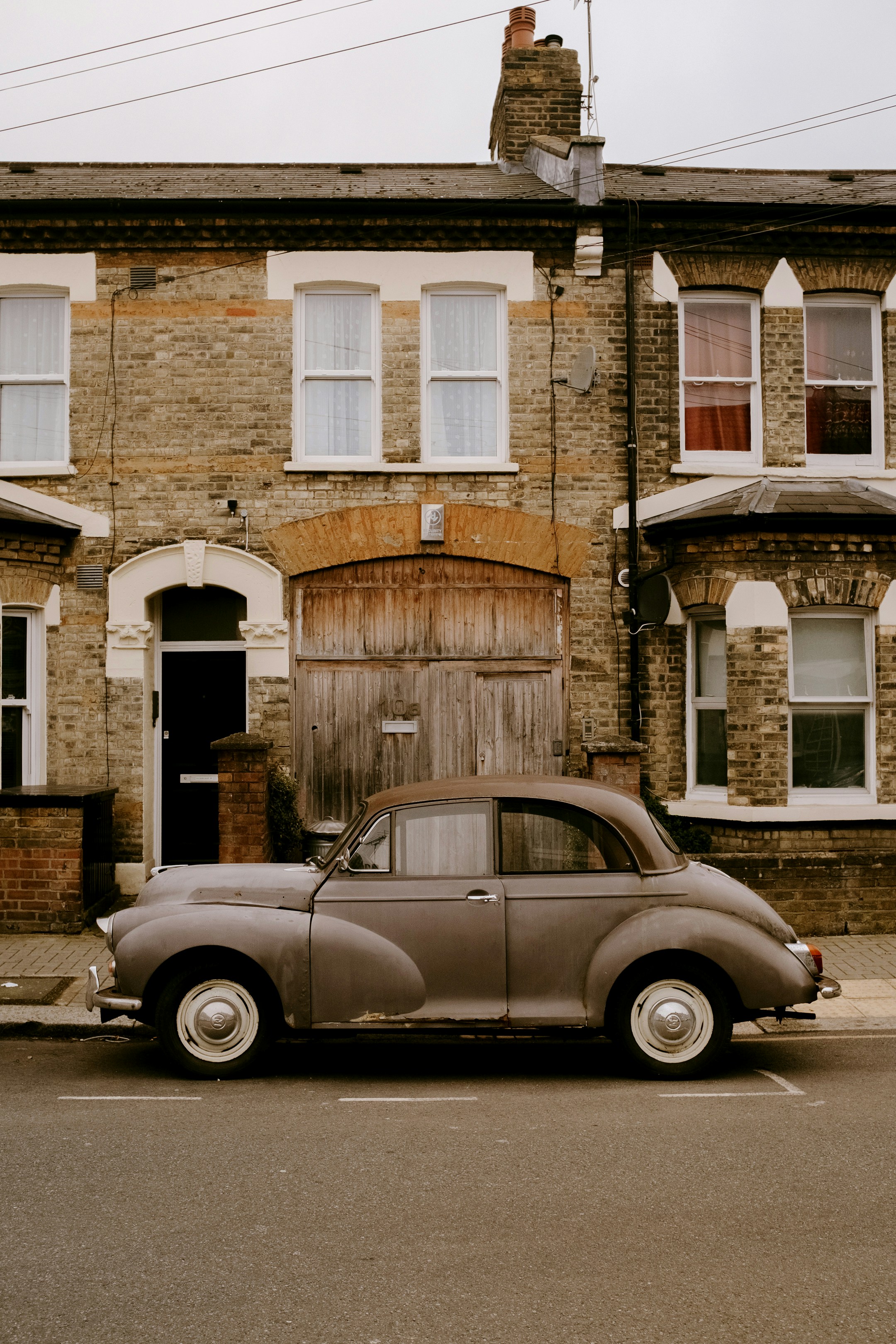 white classic car parked beside brown brick building