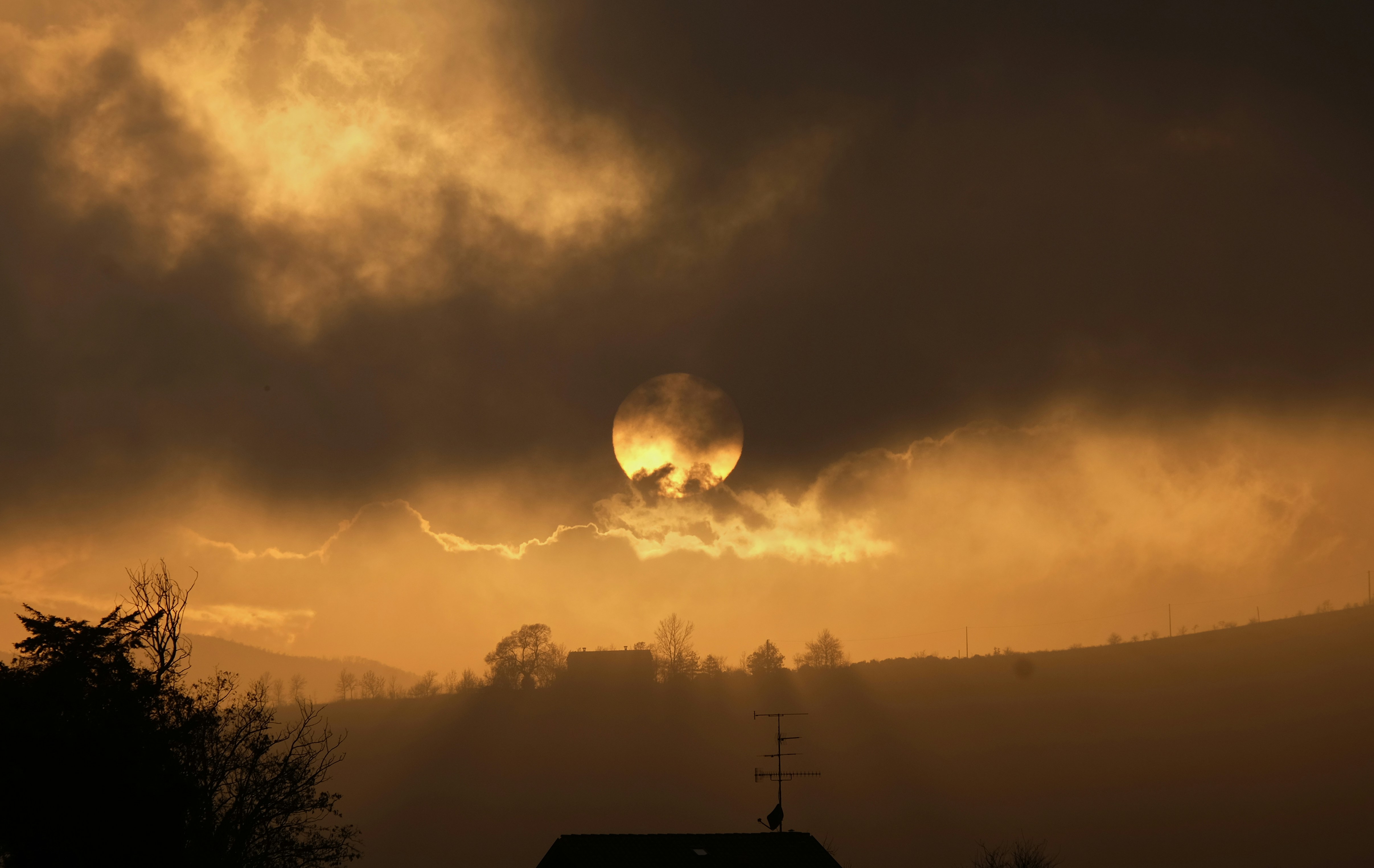 Golden Sphere Above the Horizon: Sun Piercing Through Cloud Veils