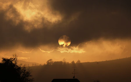 Golden Sphere Above the Horizon: Sun Piercing Through Cloud Veils