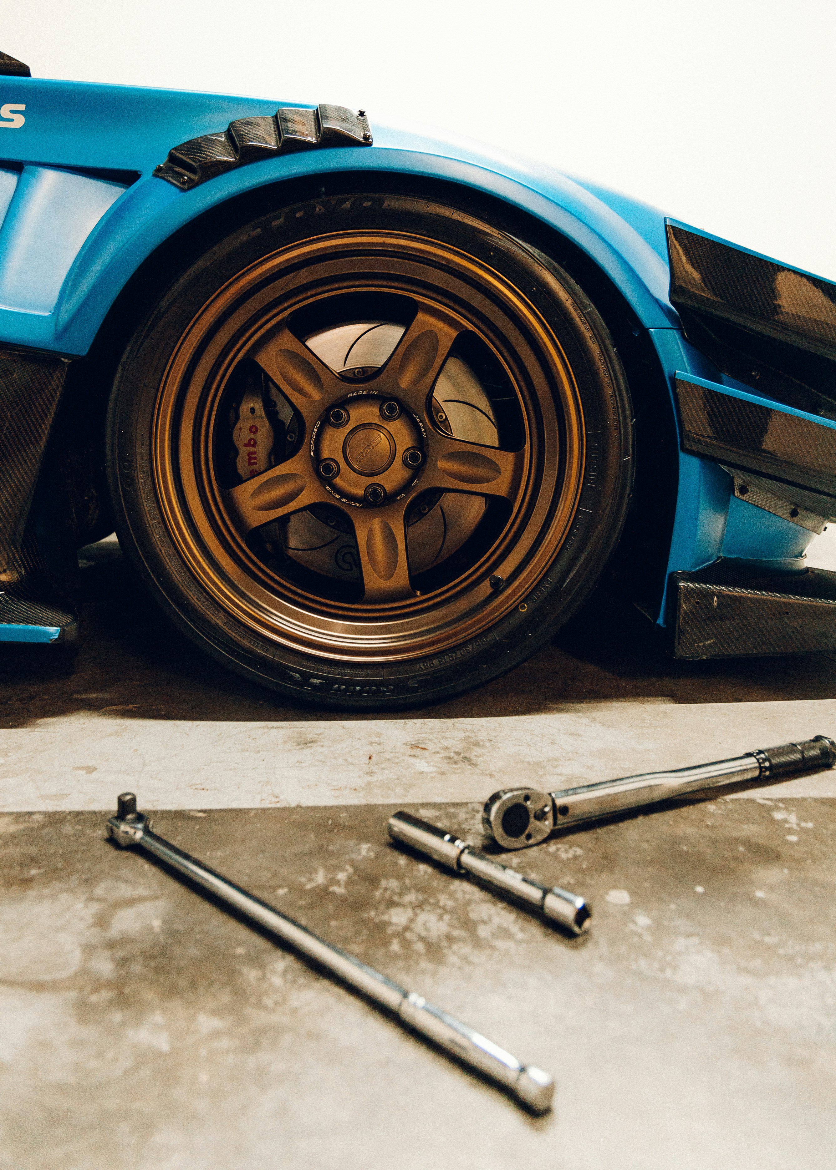 Bronze-rimmed fury: close view of a race car wheel and toolkit