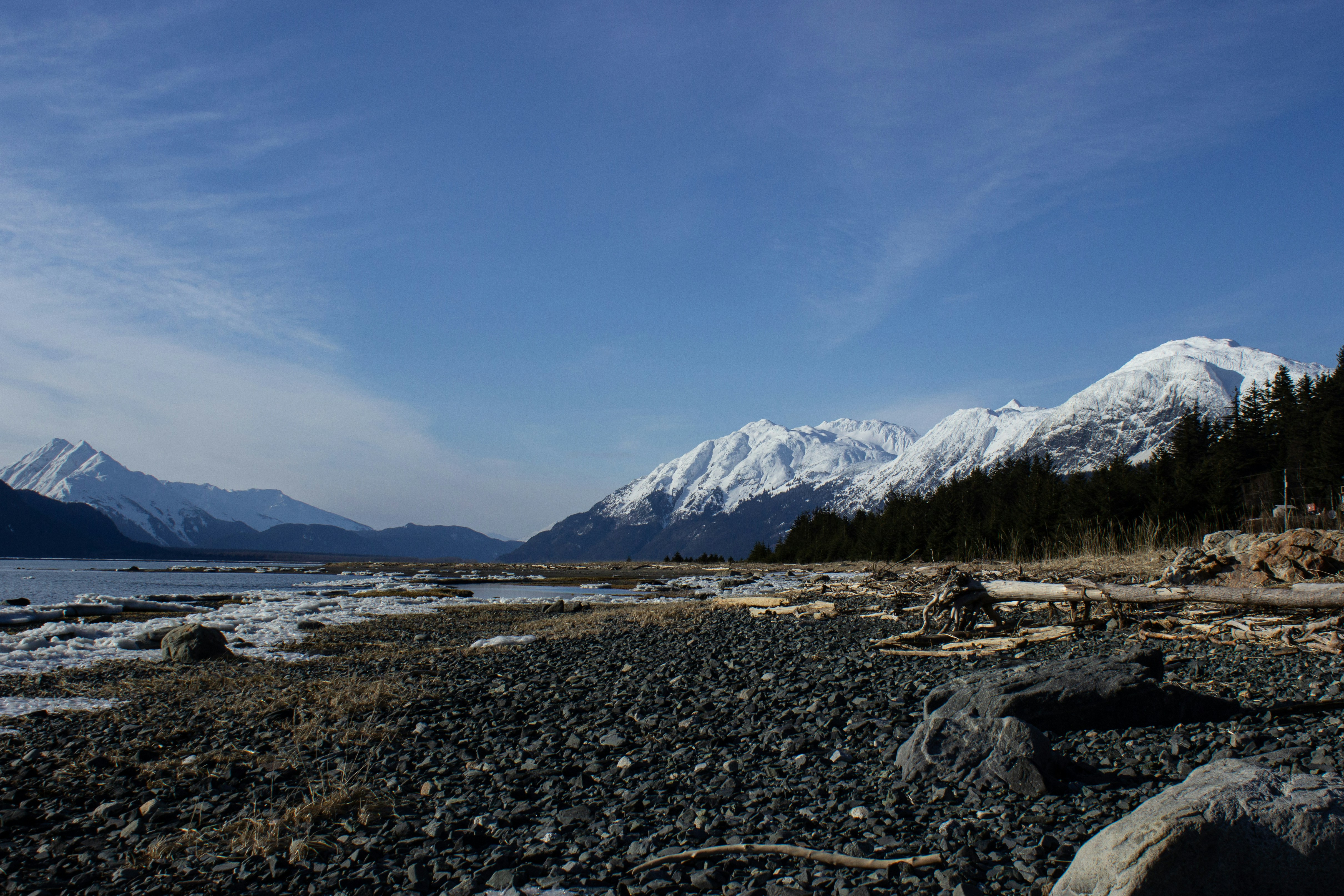 Snow-Capped Peaks Framed by a Pebble Beach Lakeshore