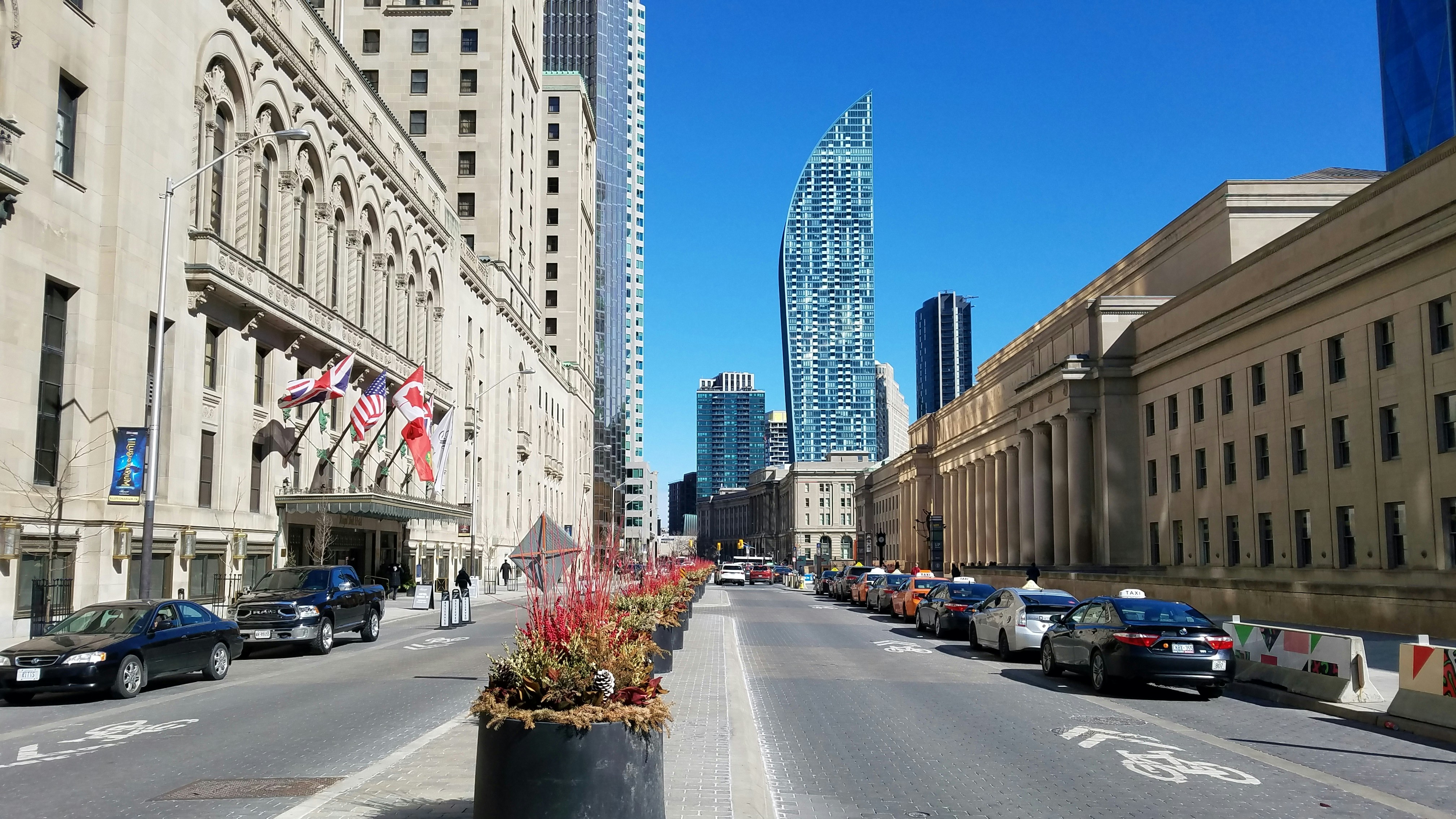 Cars parked on side of the road near high rise buildings during daytime ...