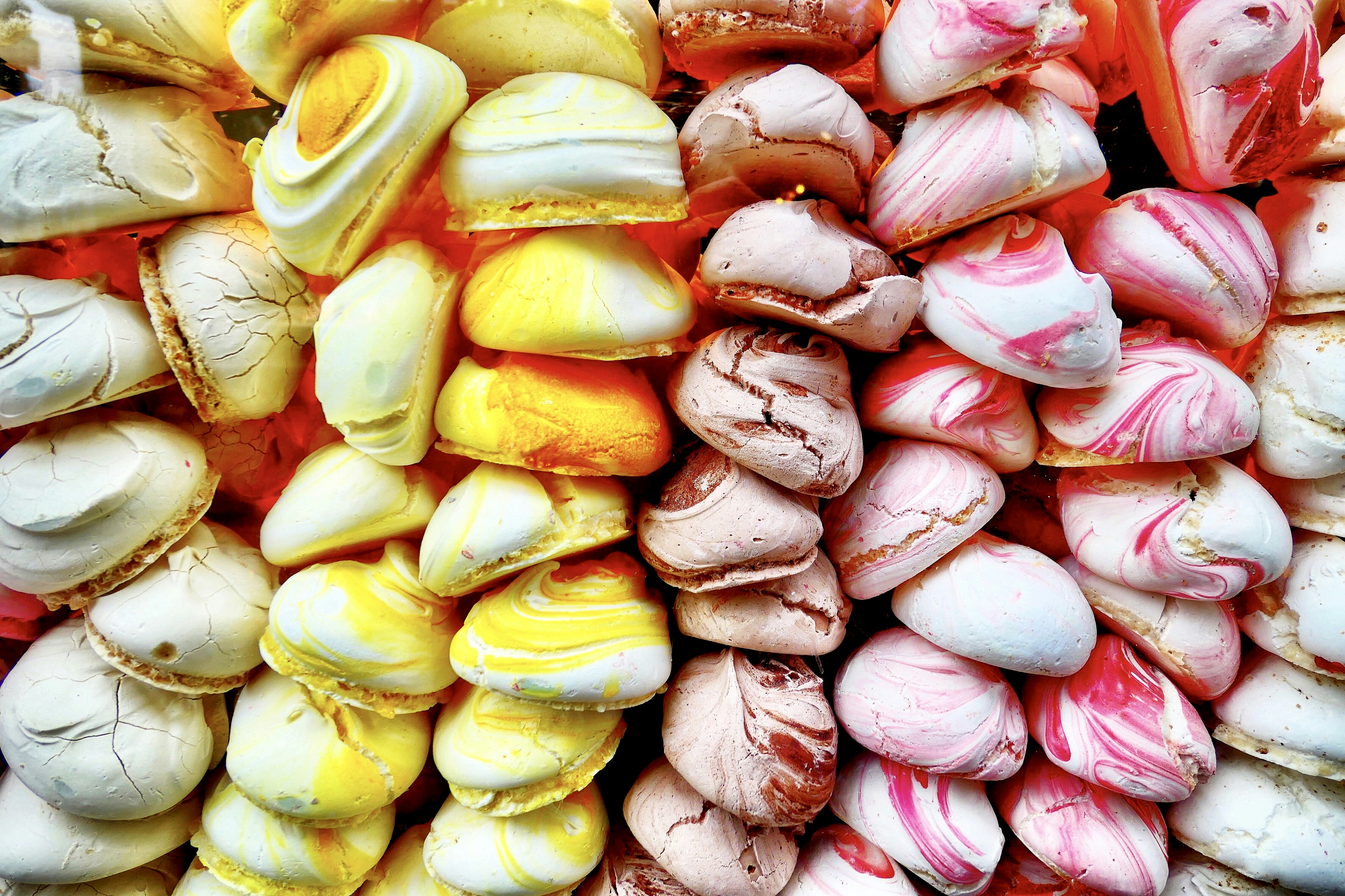 A vibrant display of assorted meringues in pastel colors, showcasing intricate swirls and textures. The arrangement highlights the delightful variety of flavors and artistry in confectionery design.