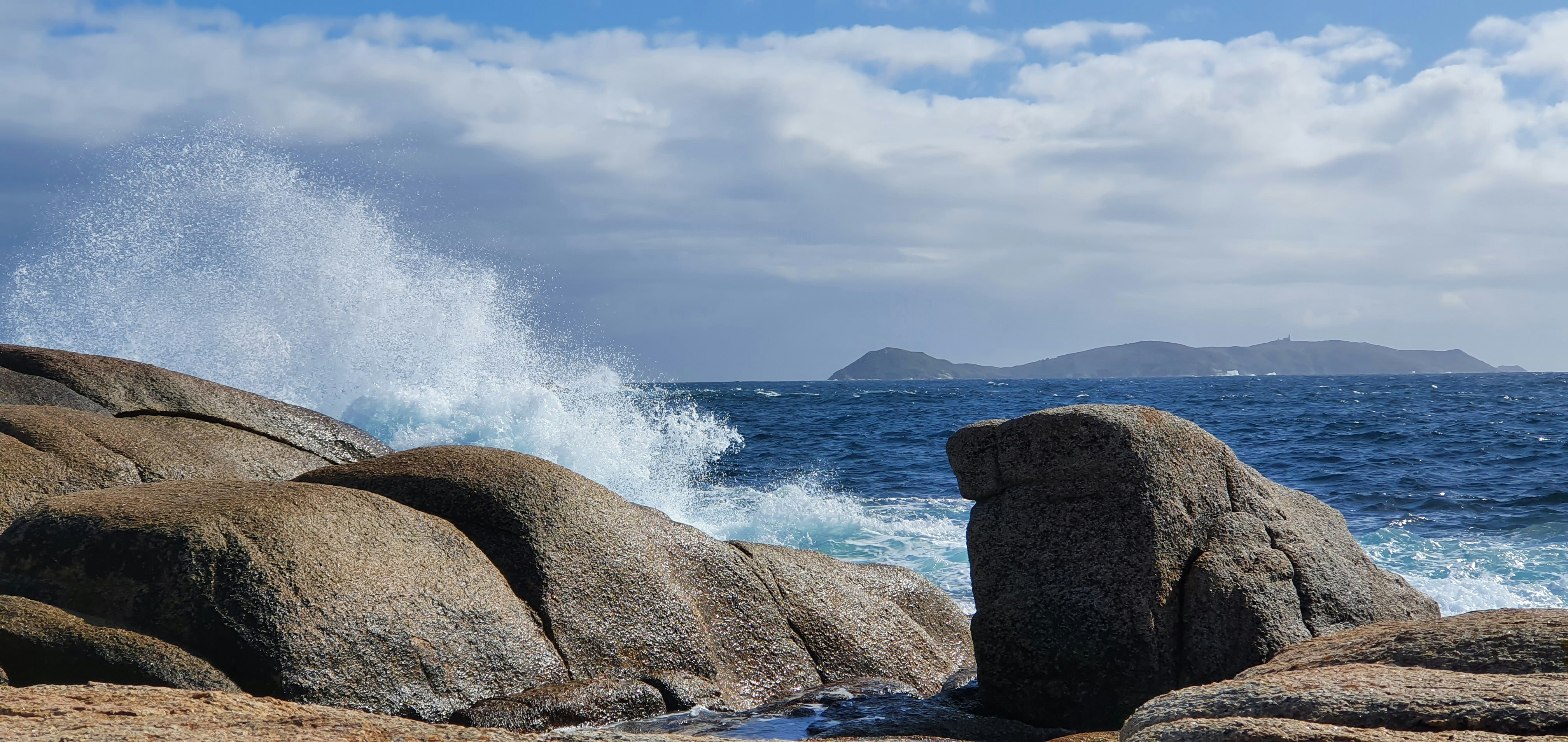 Granite Clash: Sea Spray Arches Over a Rocky Shore