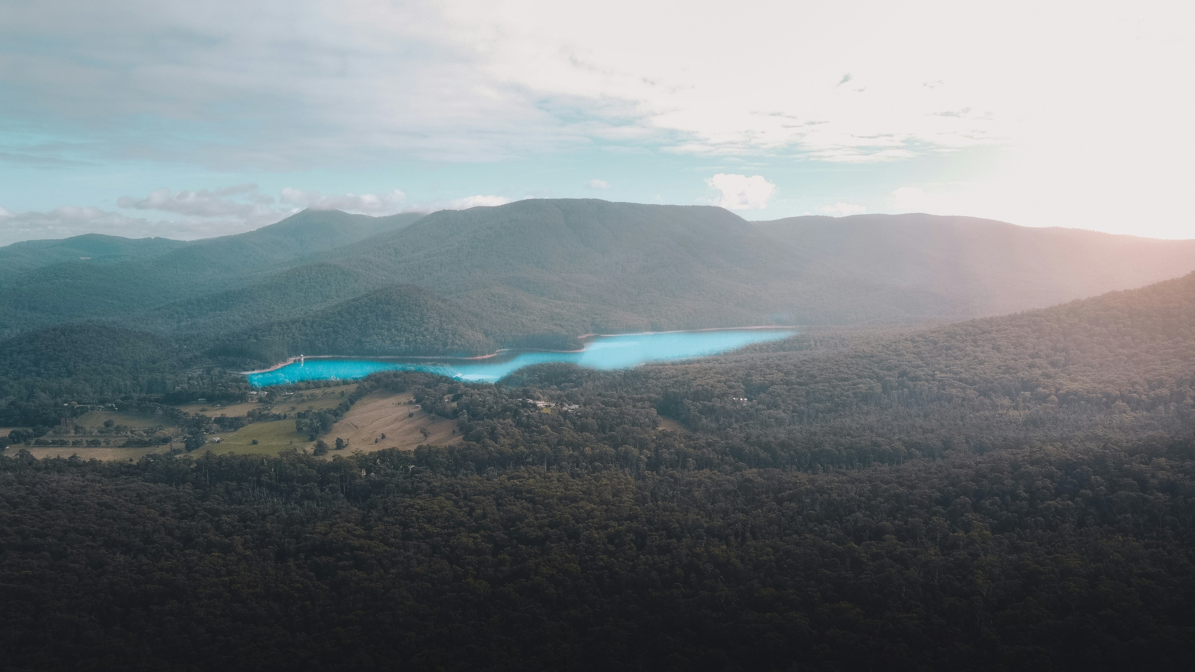 Azure Ribbon over the Emerald Basin: Dawn Flight Above a Mountain Valley