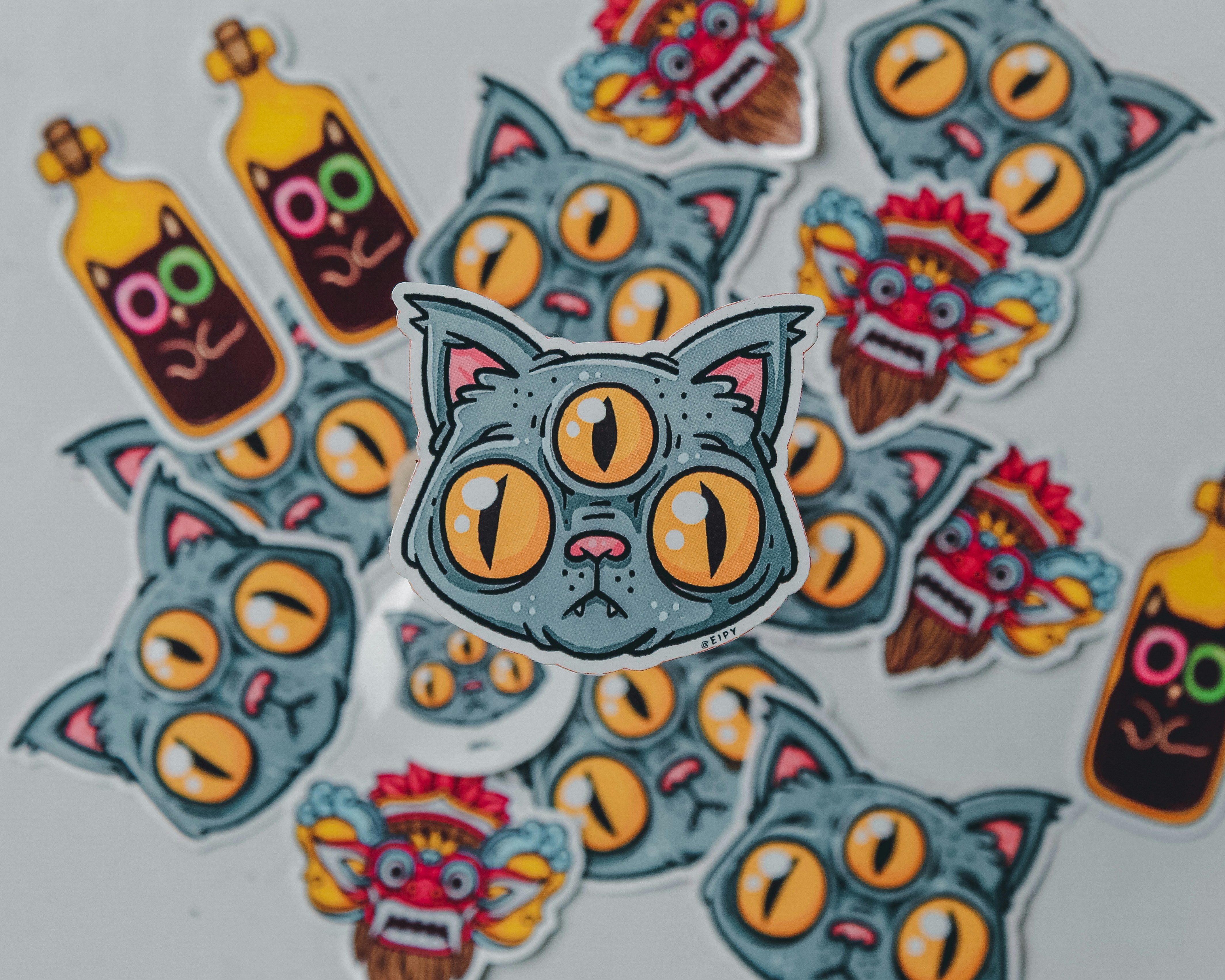 Colorful assortment of cartoon stickers featuring a three-eyed cat and various quirky characters. A playful blend of designs on a light background.