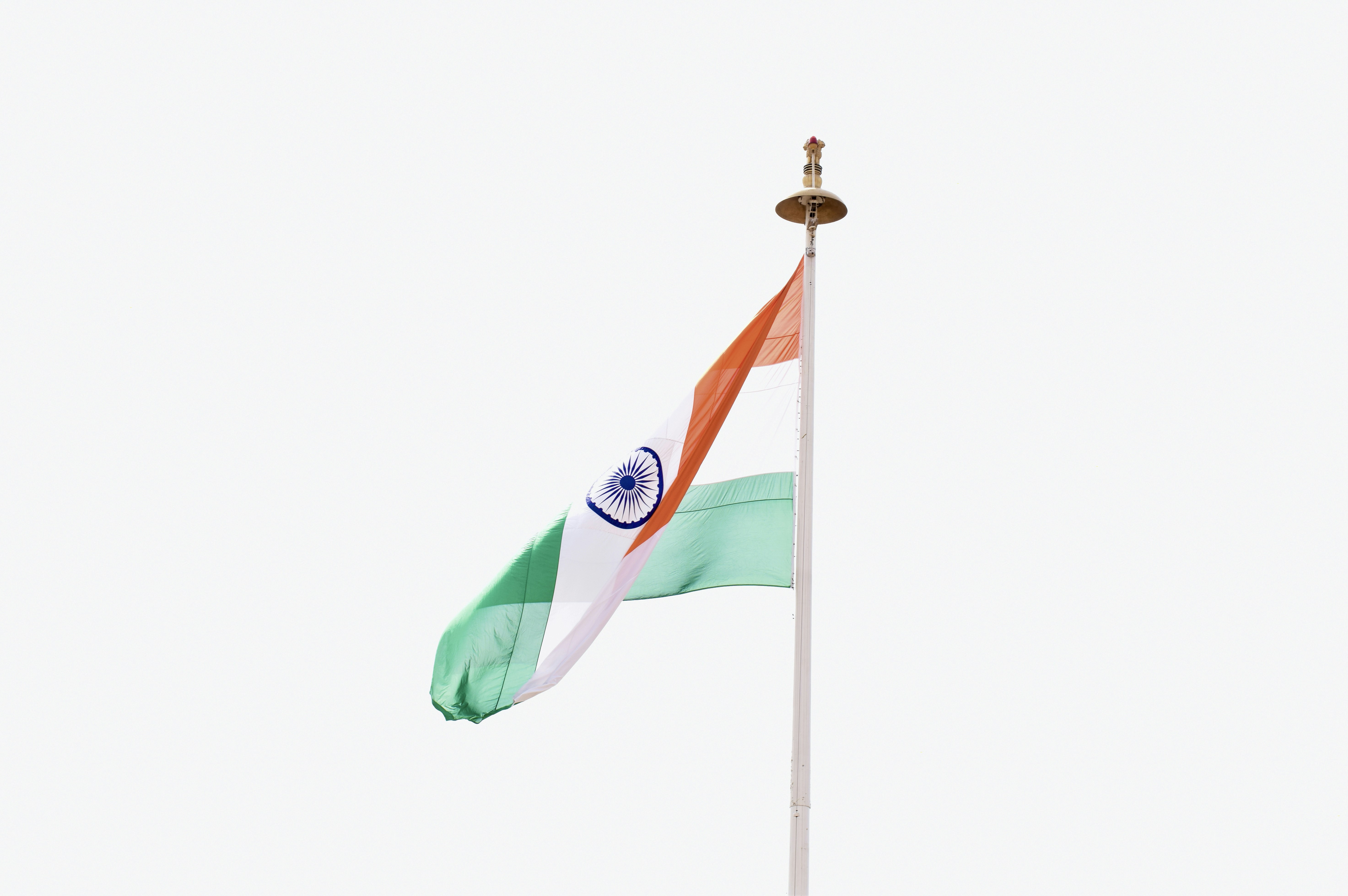 The Indian national flag billows gracefully against a clear sky, showcasing its vibrant colors and intricate design.