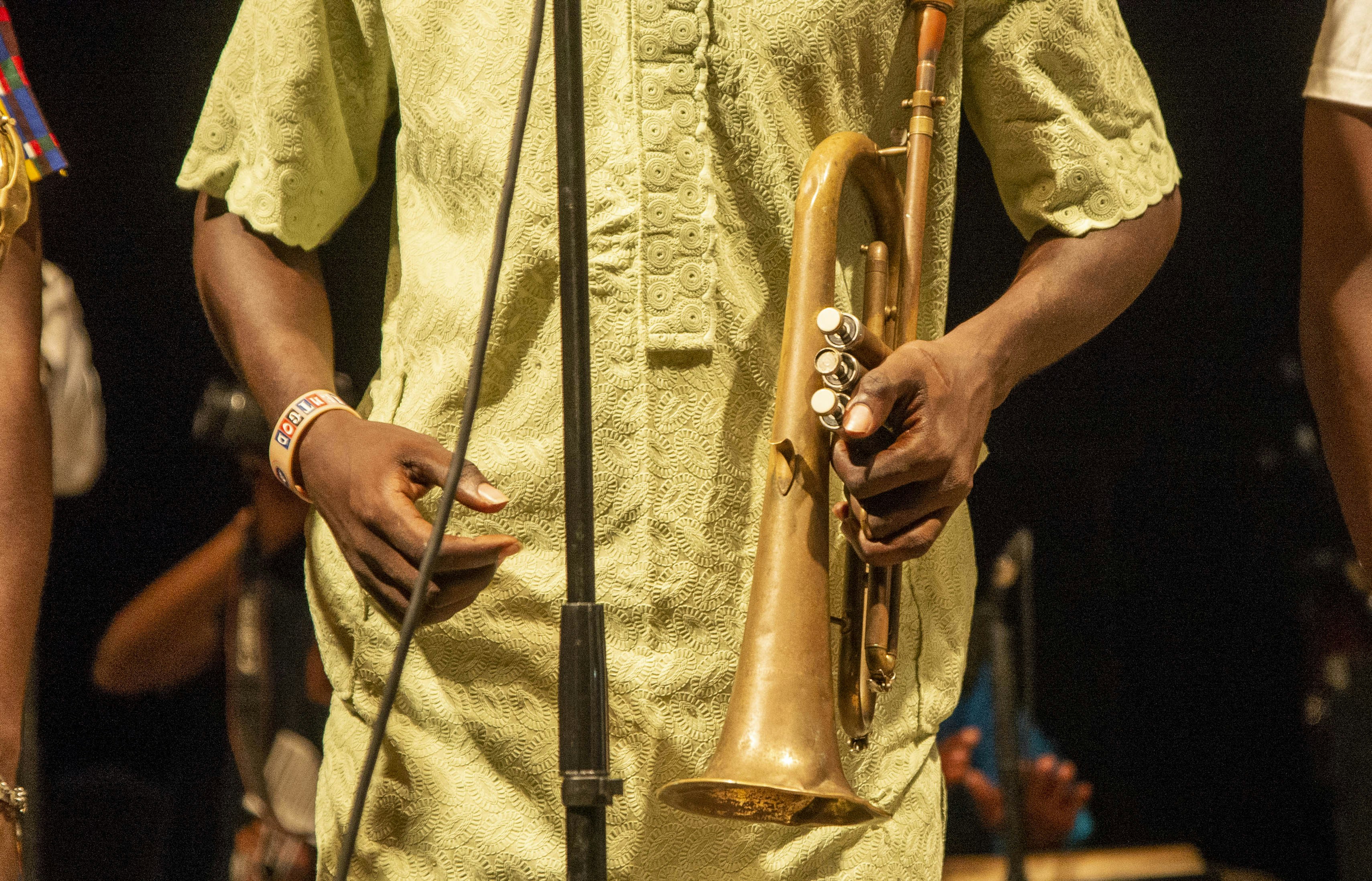Brass in Focus: Hands Guiding a Trumpet Under Stage Lights