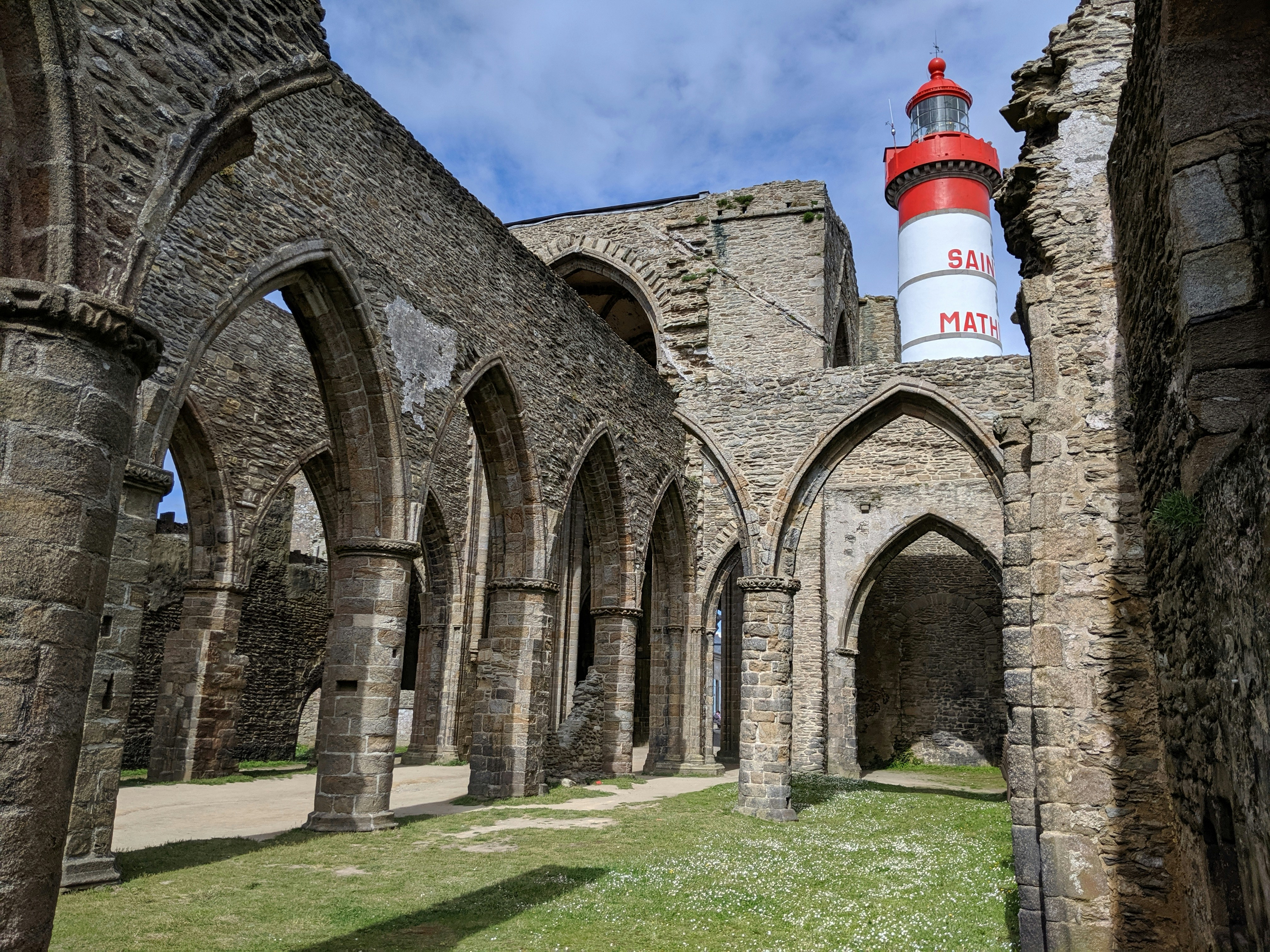 Ruins and Lighthouse: Stone Arches Framing a Harbor Beacon