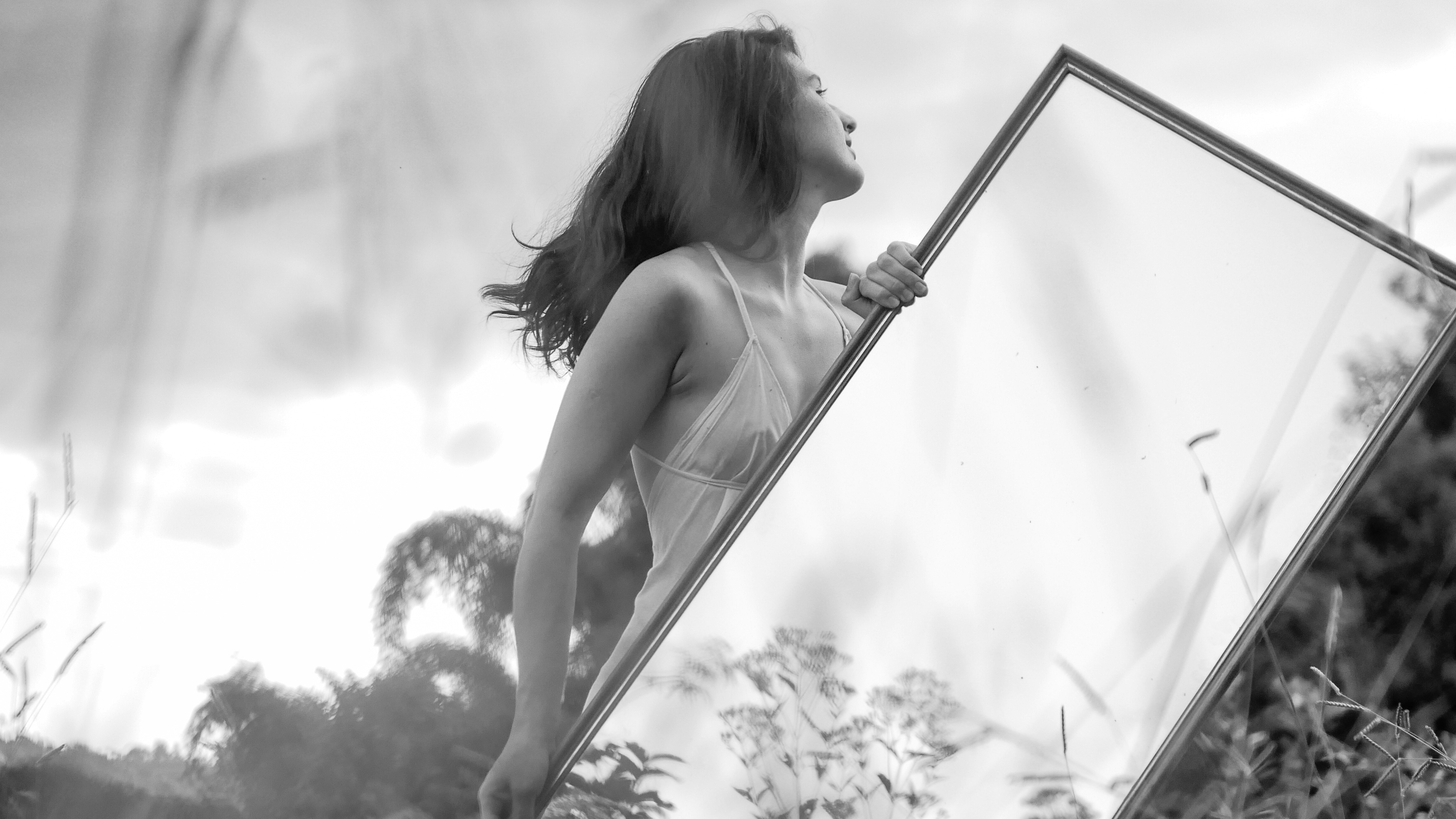 Tilted Echo: A Grayscale Portrait Framed by a Leaning Mirror