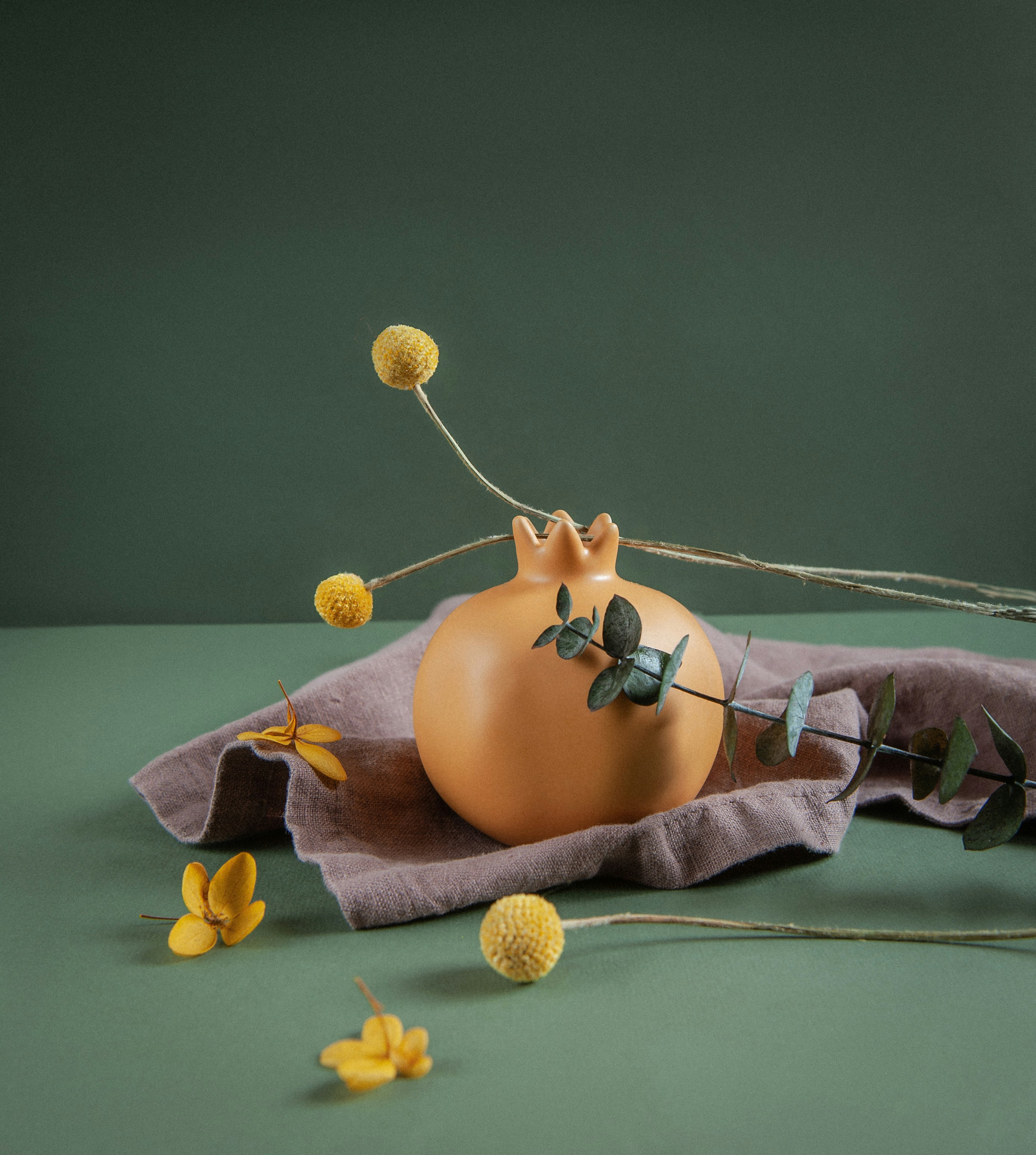 Orange ceramic fruit centerpiece with billy buttons and eucalyptus on a lavender cloth